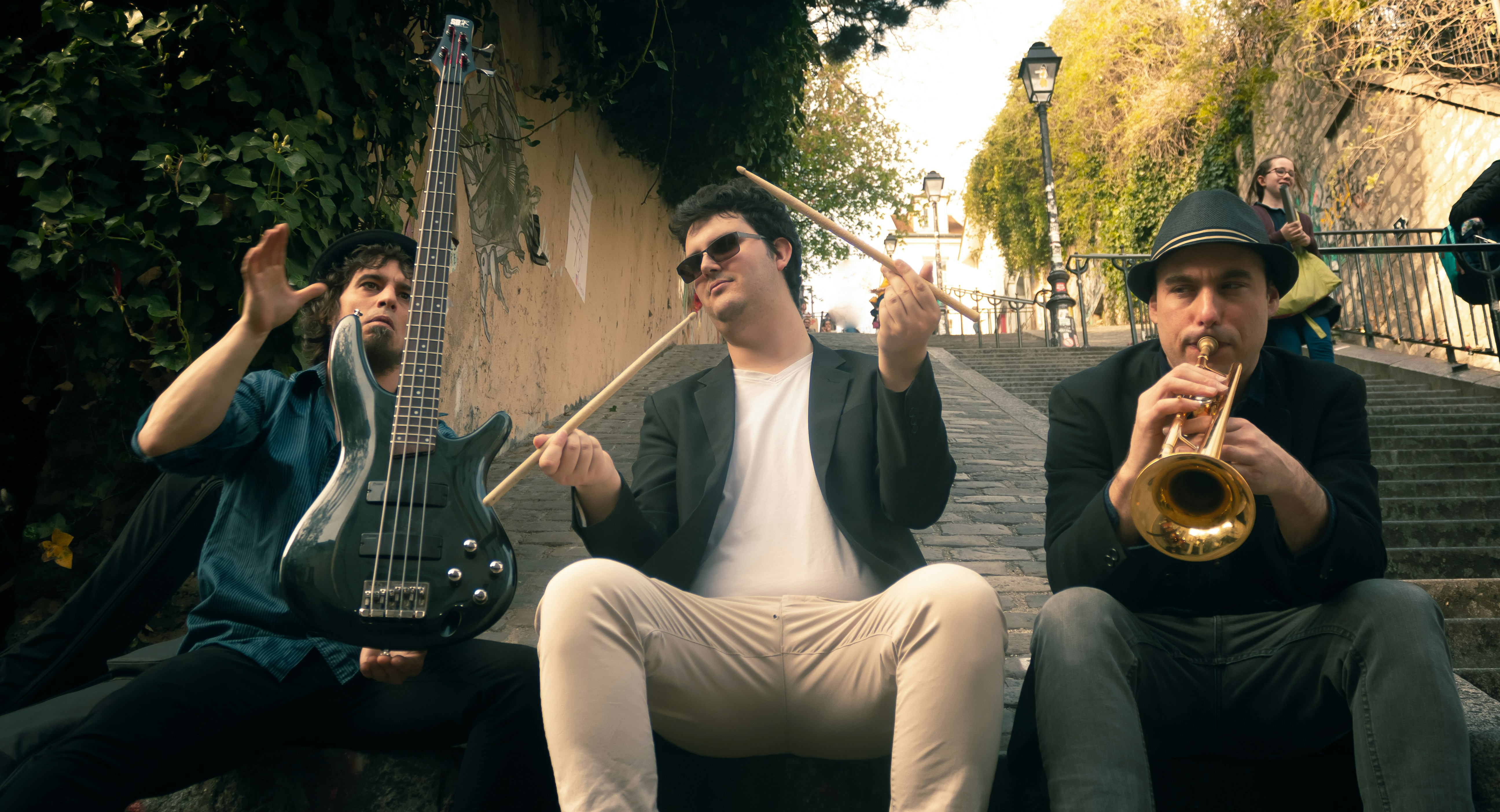 Three men playing musical instruments while sitting on ramp beside ...