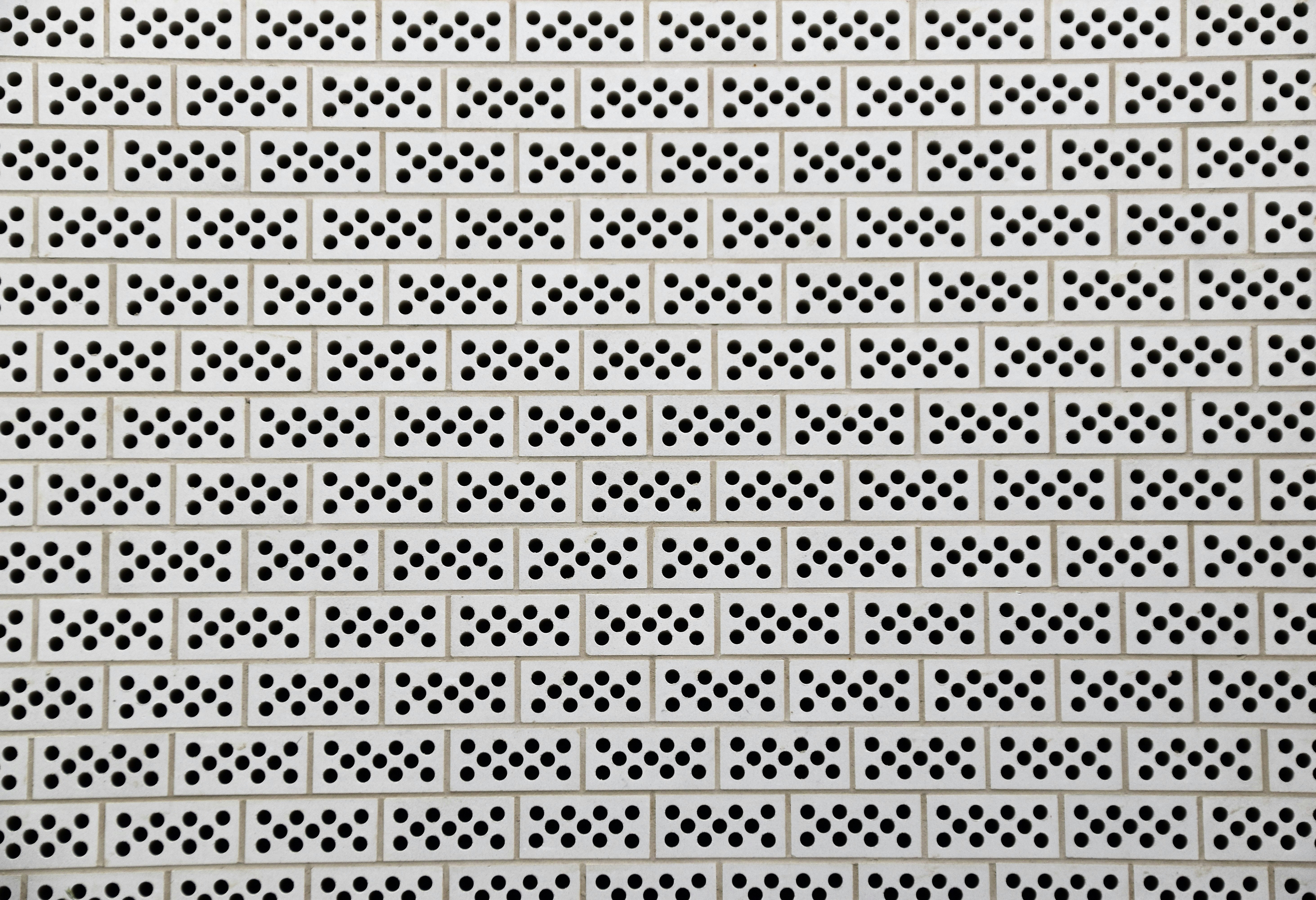 A white perfored wall with black dots on it photo – Free Pattern Image ...