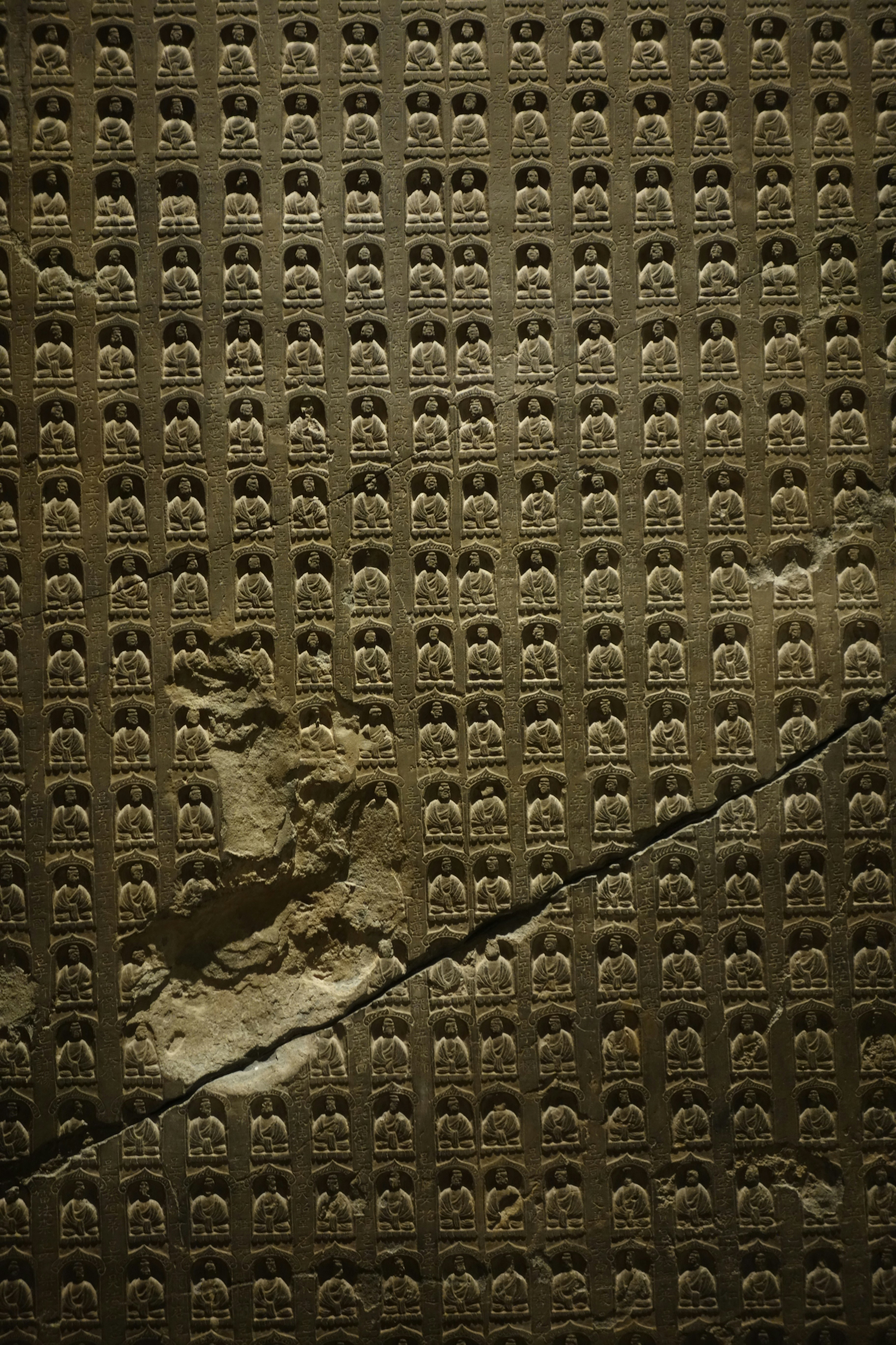 Ritual Wall of Repose: A Grid of Tiny Buddhas Beneath a Fractured Vein