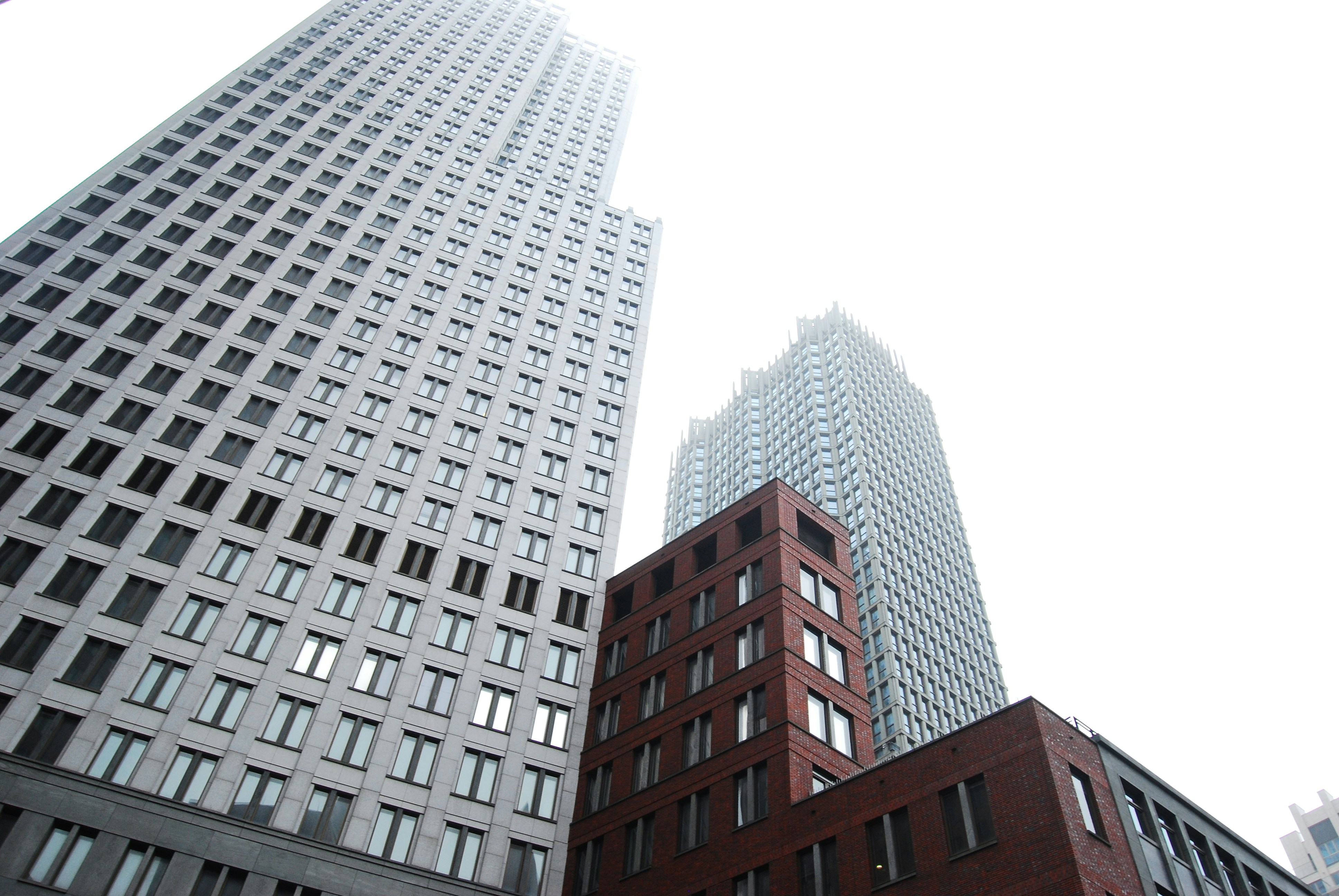 Skyscrapers rise into a foggy sky, blending modern architecture with atmospheric haze.