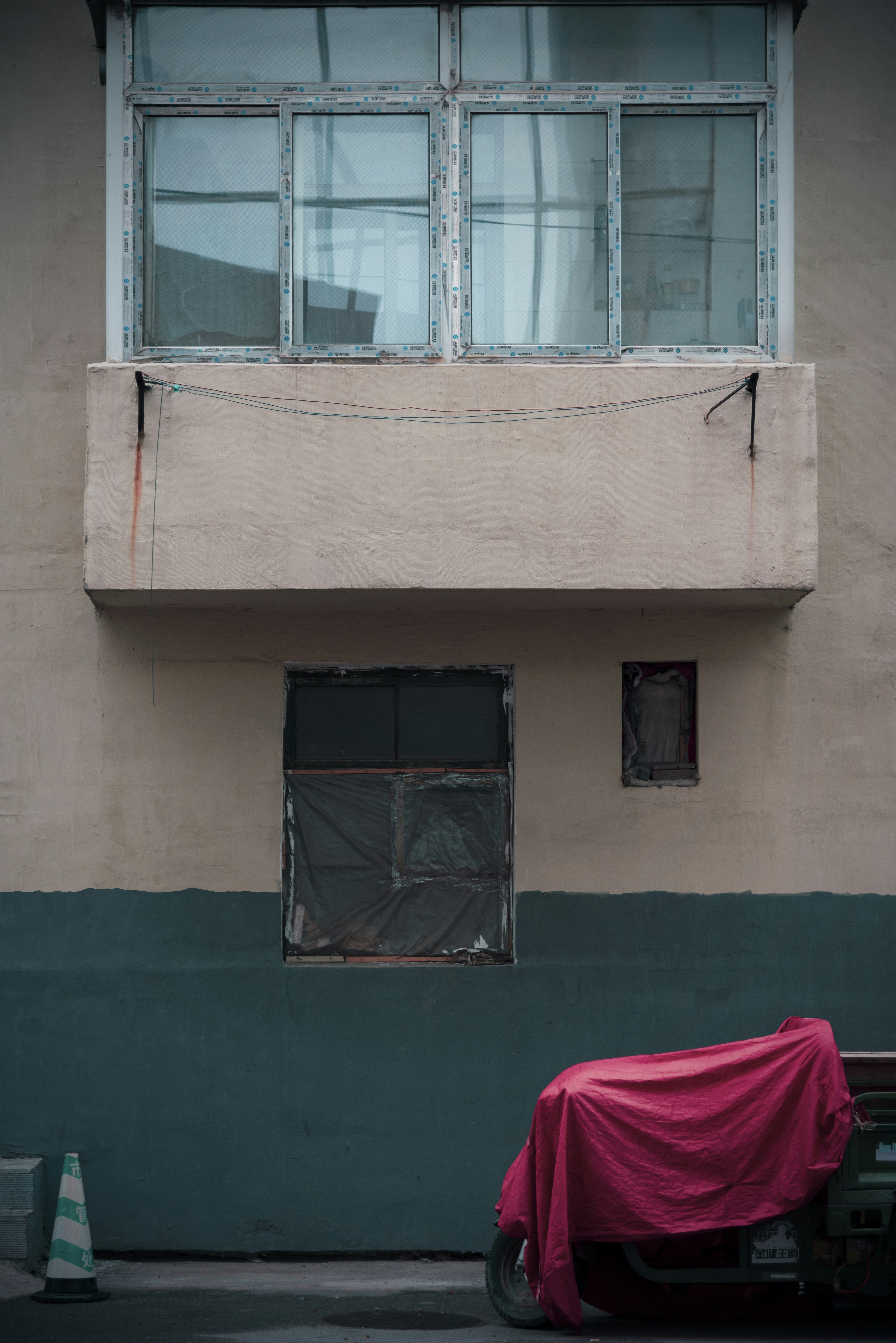 Crimson Draped Motorcycle Under a Weathered Balcony