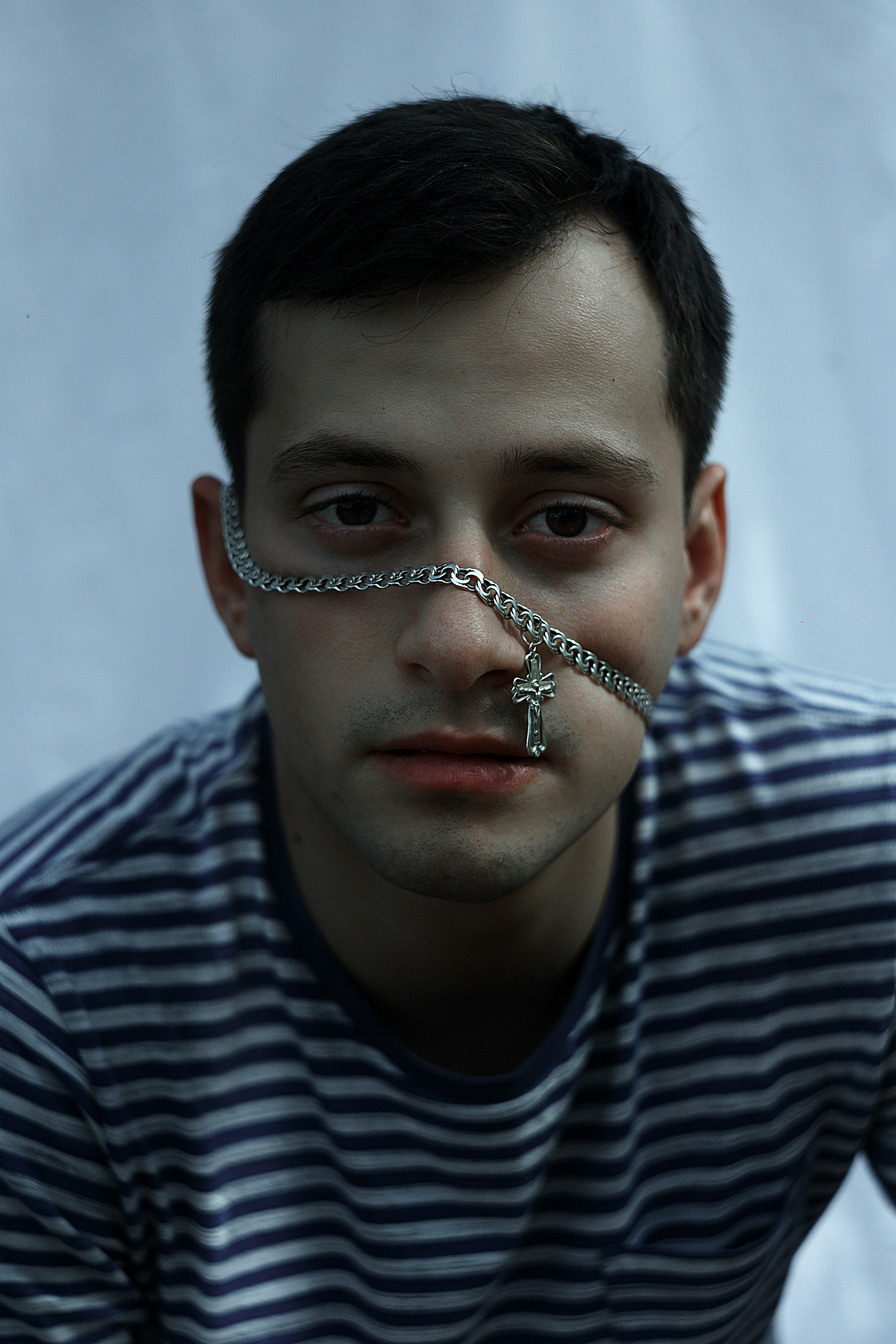 Close-up of a contemplative portrait with a silver chain crossing the face