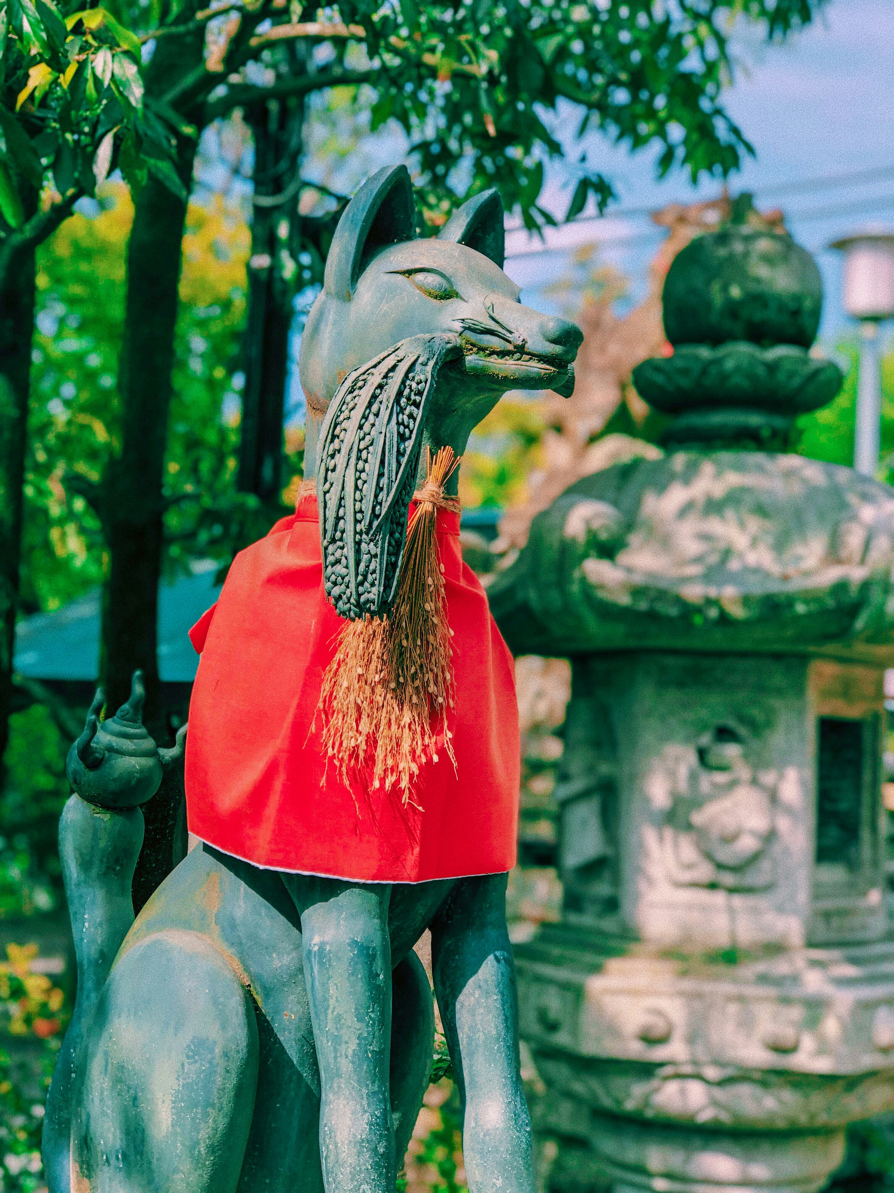 Red Cloth on a Fox Statue Amid Greenery