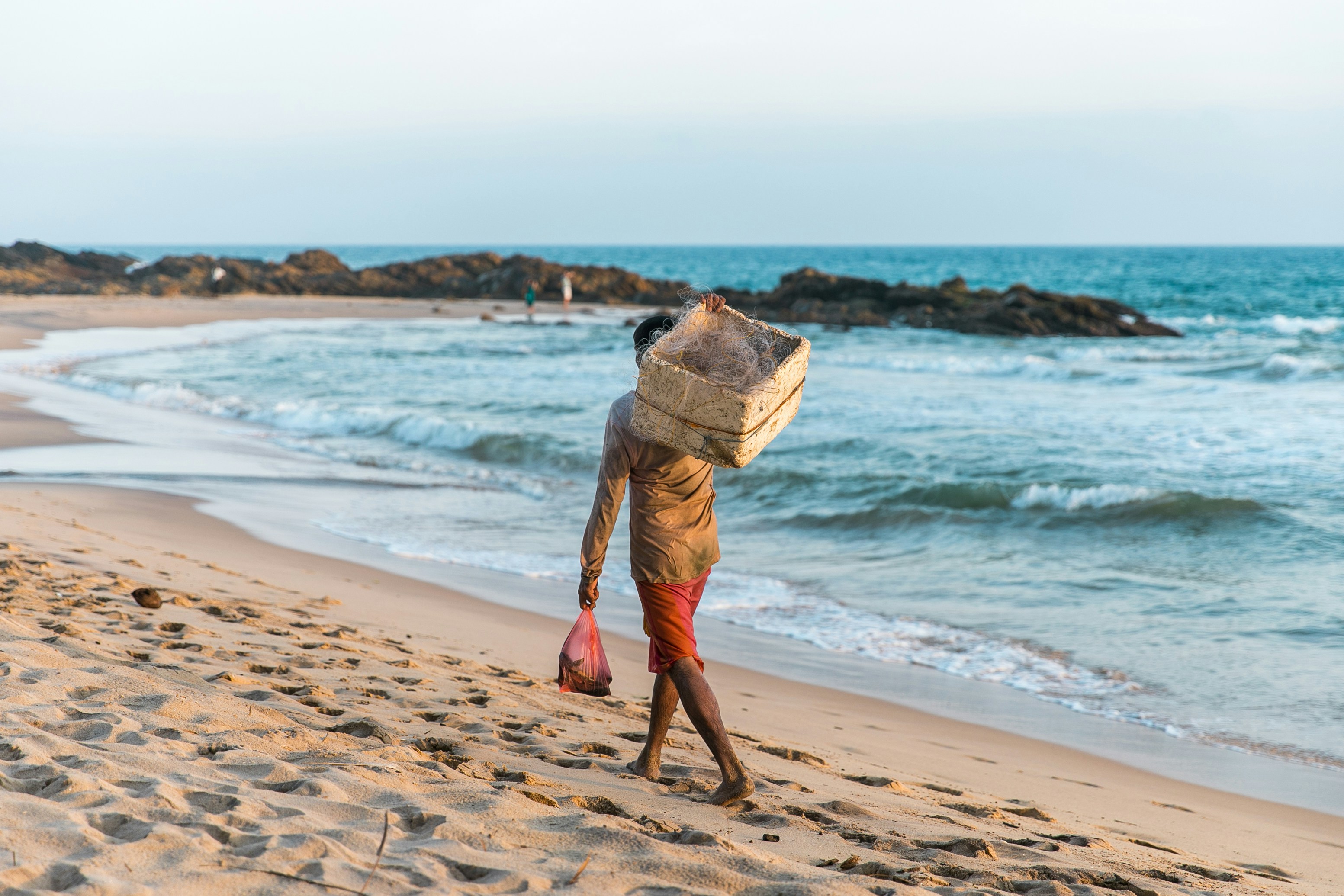 man carrying box walking beside sea
