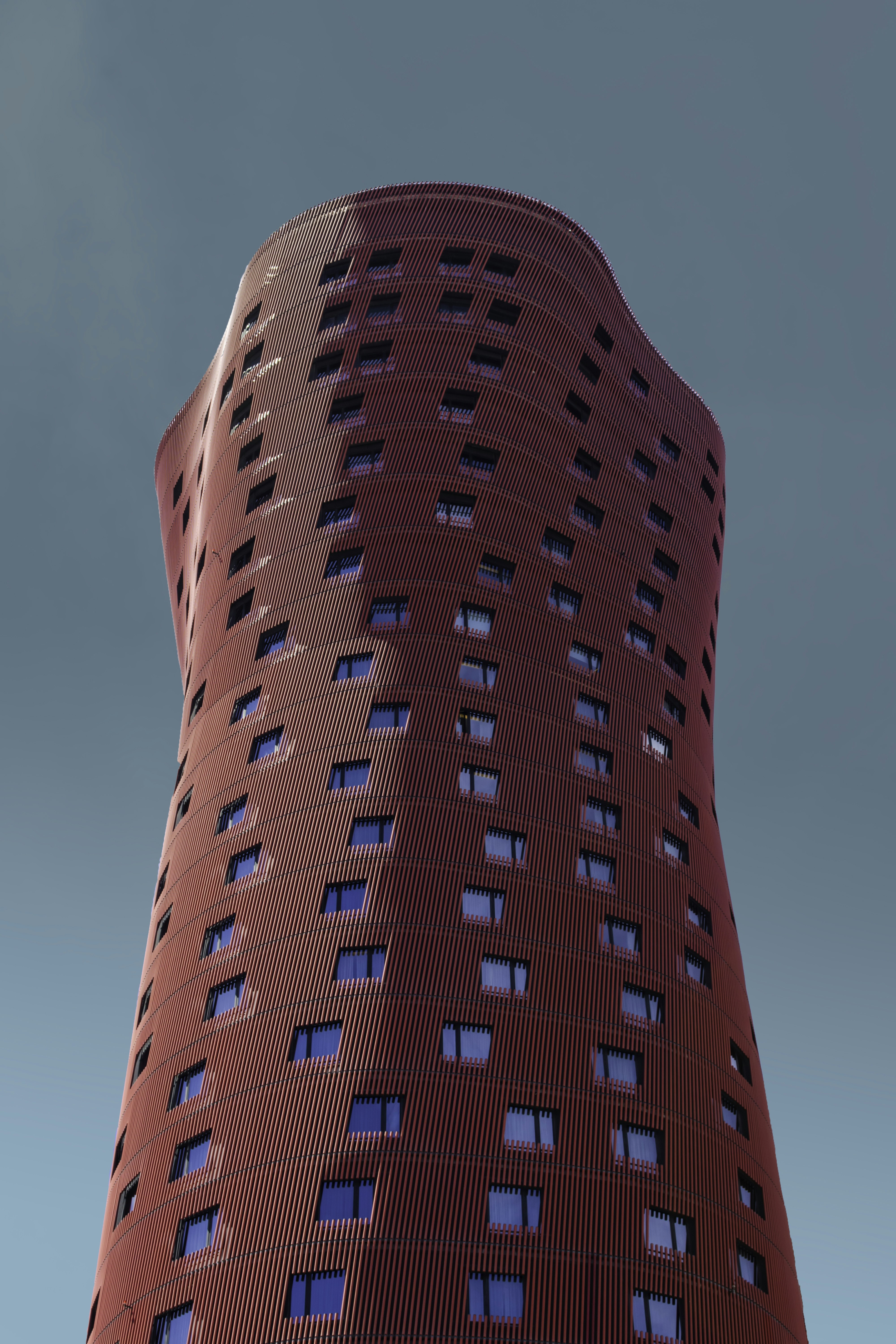 A striking modern tower with a unique façade, showcasing a pattern of windows against a clear sky.