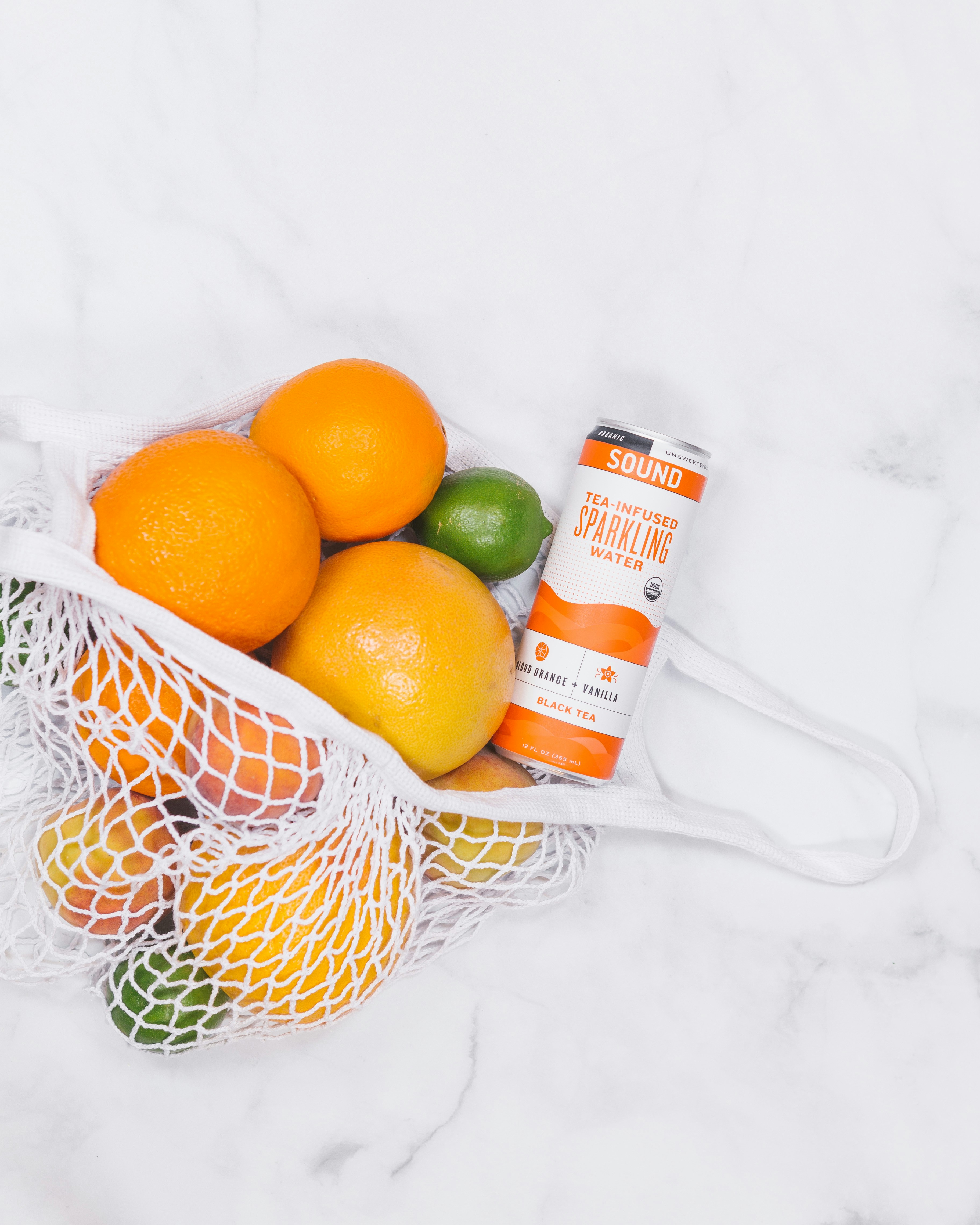 Citrus Mesh Still Life with Sparkling Water Can on Marble