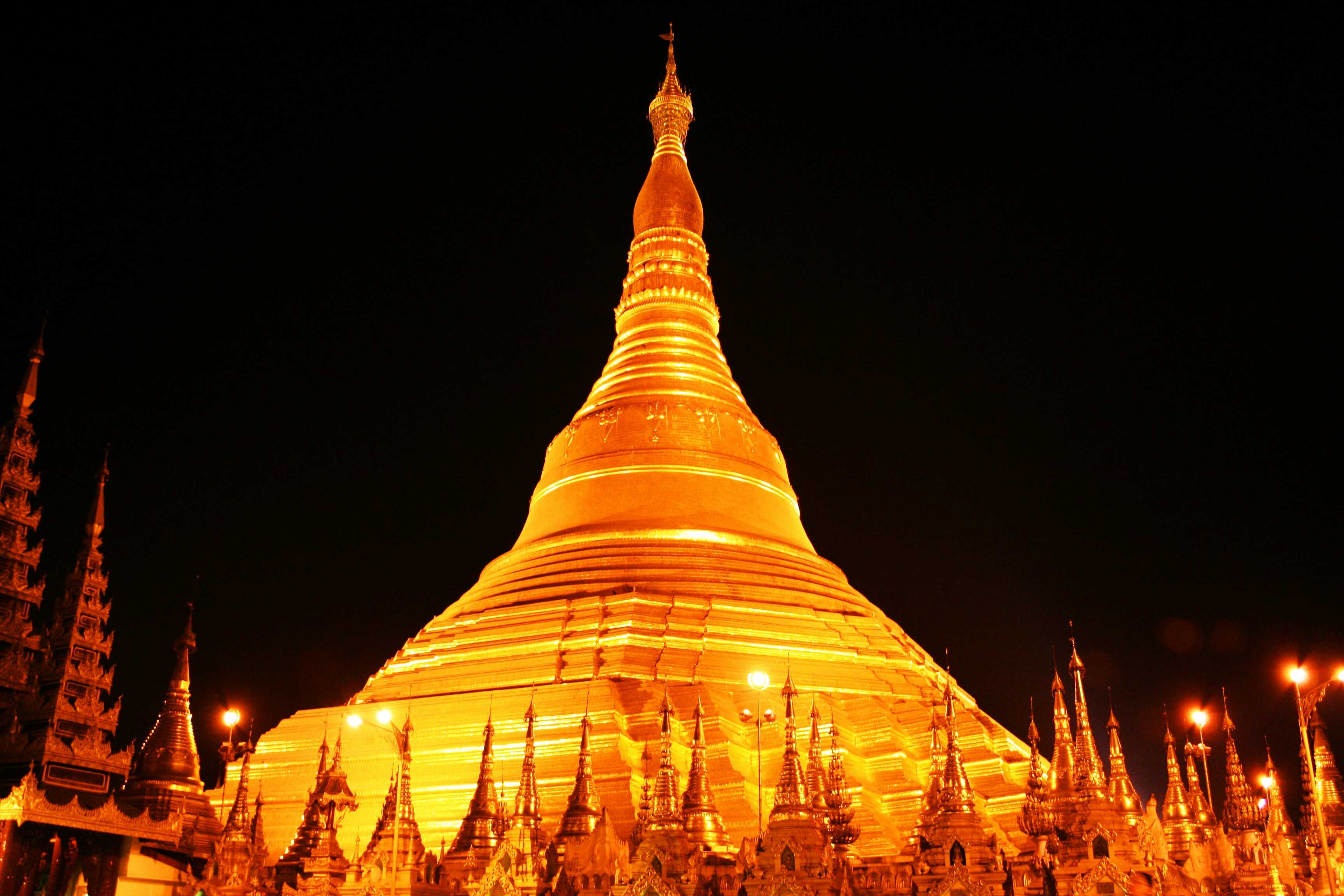 Golden stupa glowing under night sky, surrounded by intricate temple structures. The scene captures the spiritual ambiance of the site.