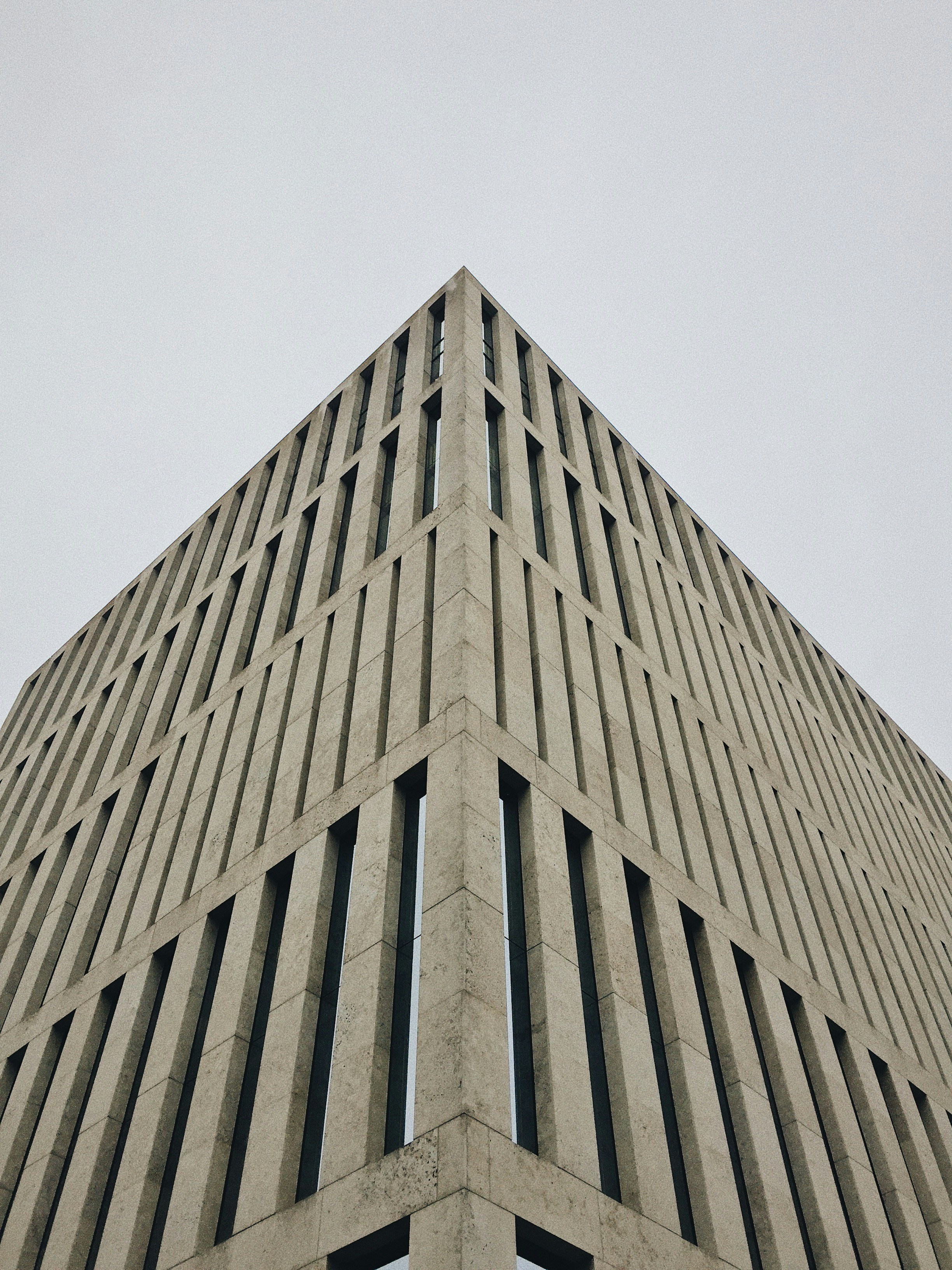Angular view of a modern building showcasing its textured concrete facade and vertical window slits.