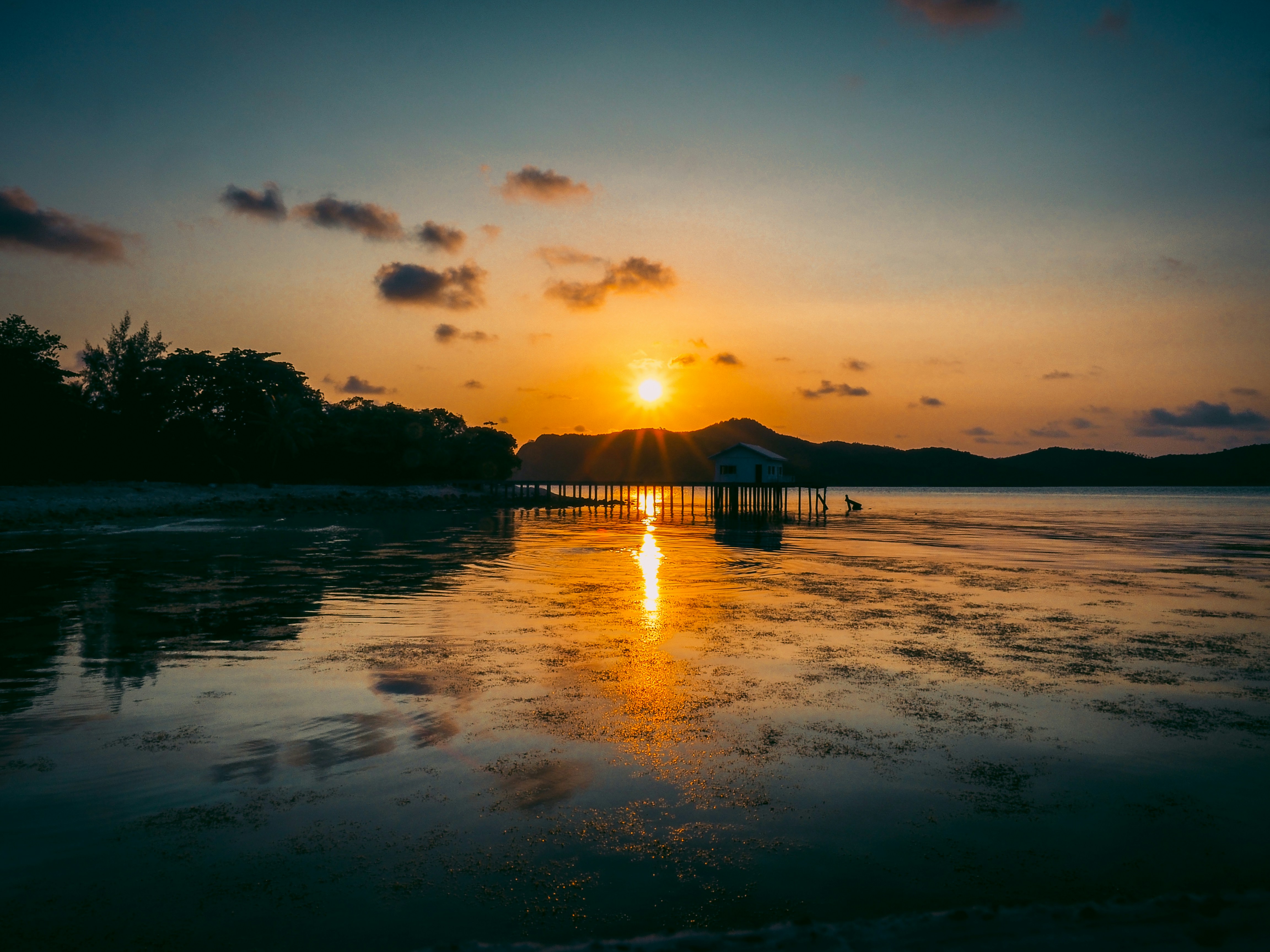 Horizon of Fire: Sunset Pier Quietly Extends Across a Calm Lagoon