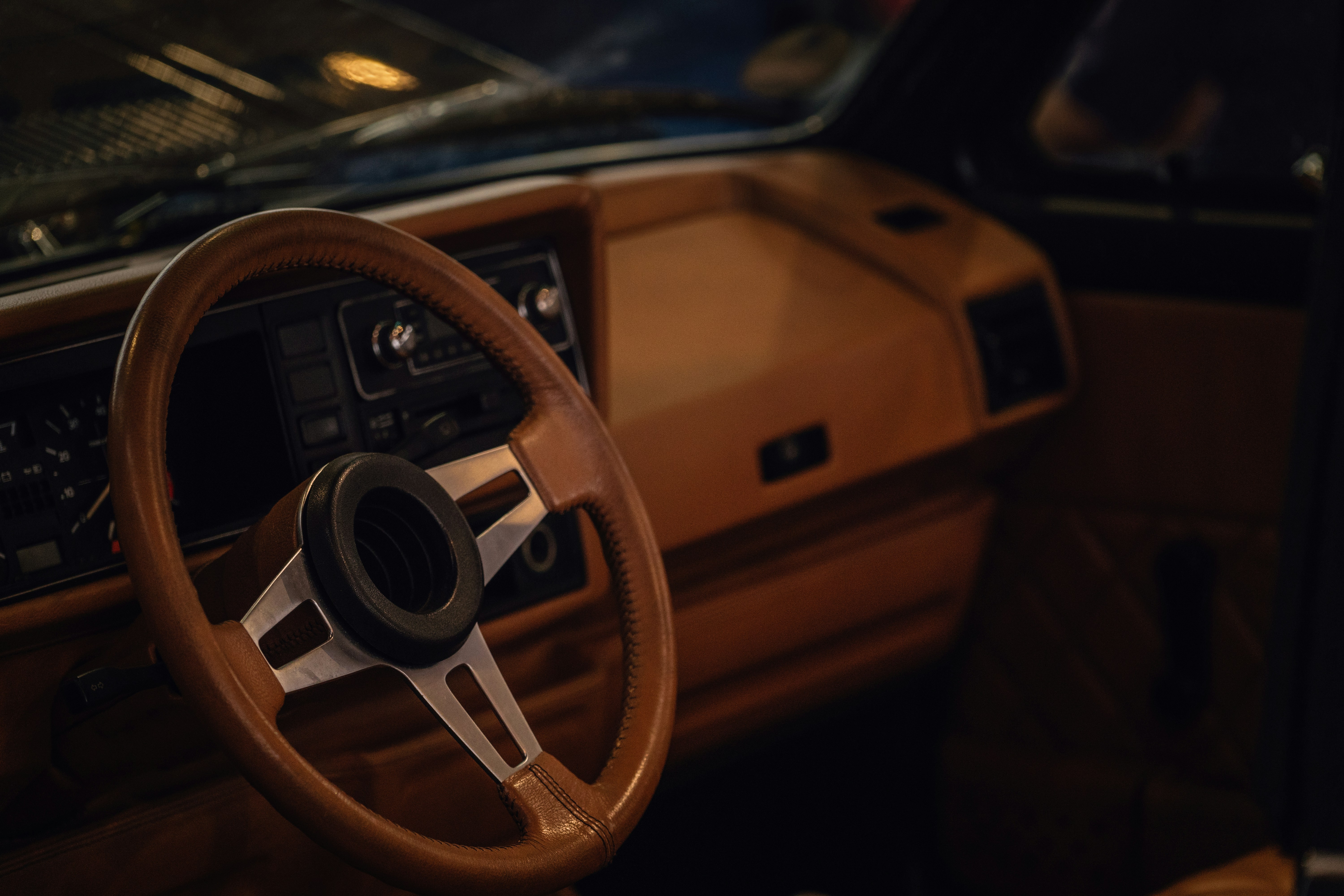 Interior view of a vintage car showcasing a stylish steering wheel and dashboard design with warm leather accents.
