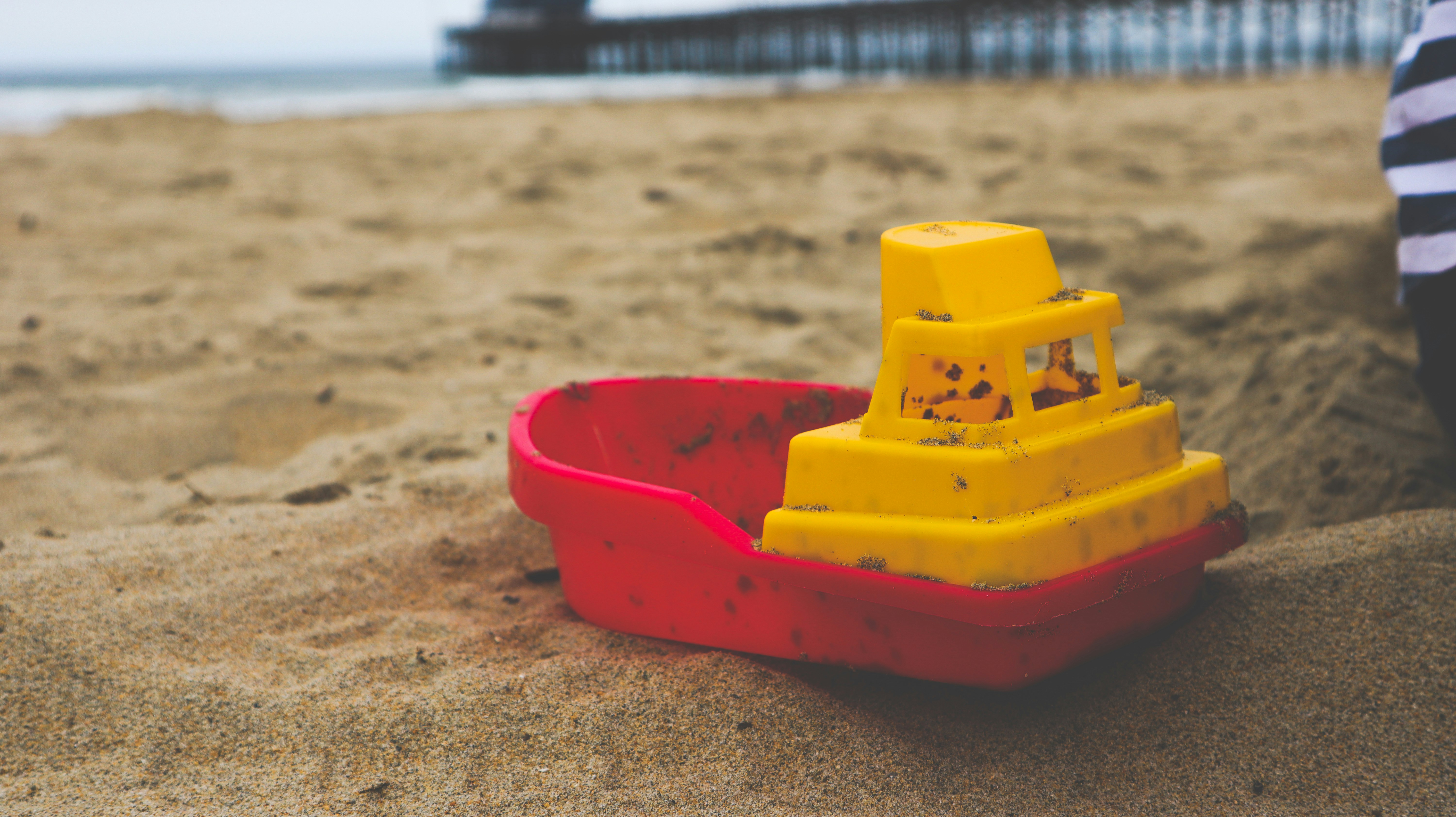 Foto Bote de plástico rojo y amarillo en la arena – Imagen Persona ...