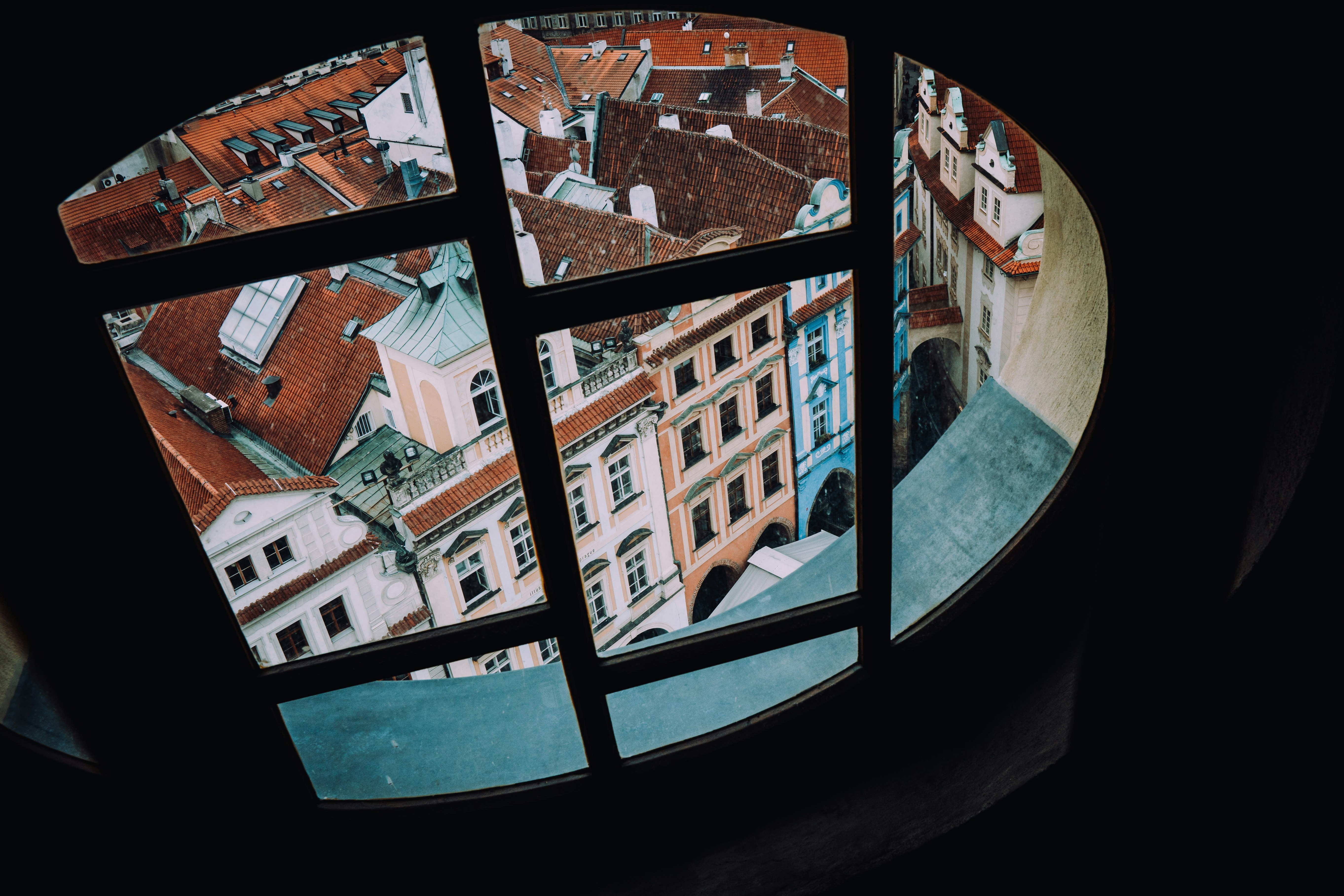 Round Window Panorama: Patchwork of Red-Tiled Rooftops Framed by Gridded Glass