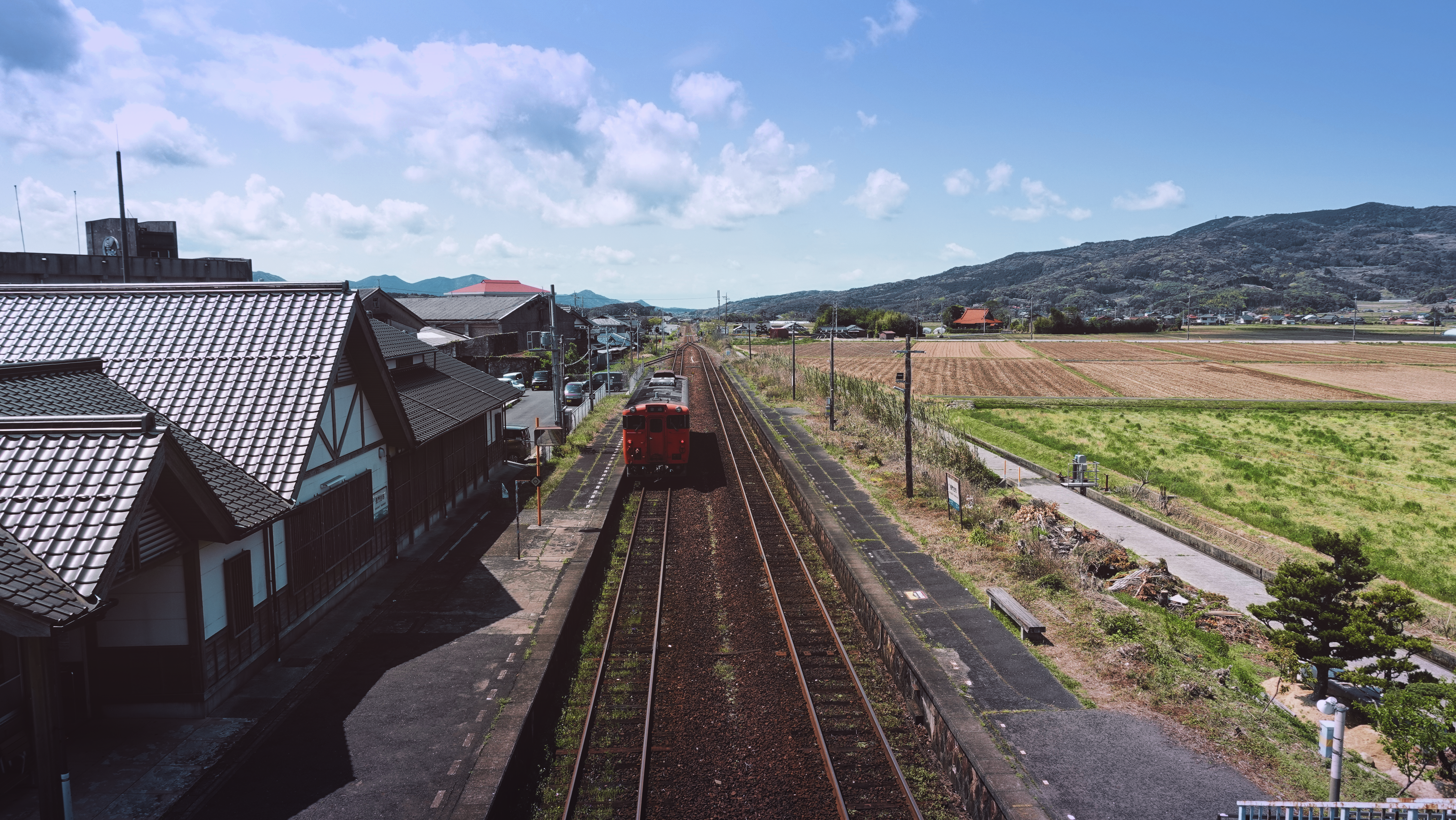Convergence on the Rural Rail: A Red Locomotive Hums Toward the Distant Hills