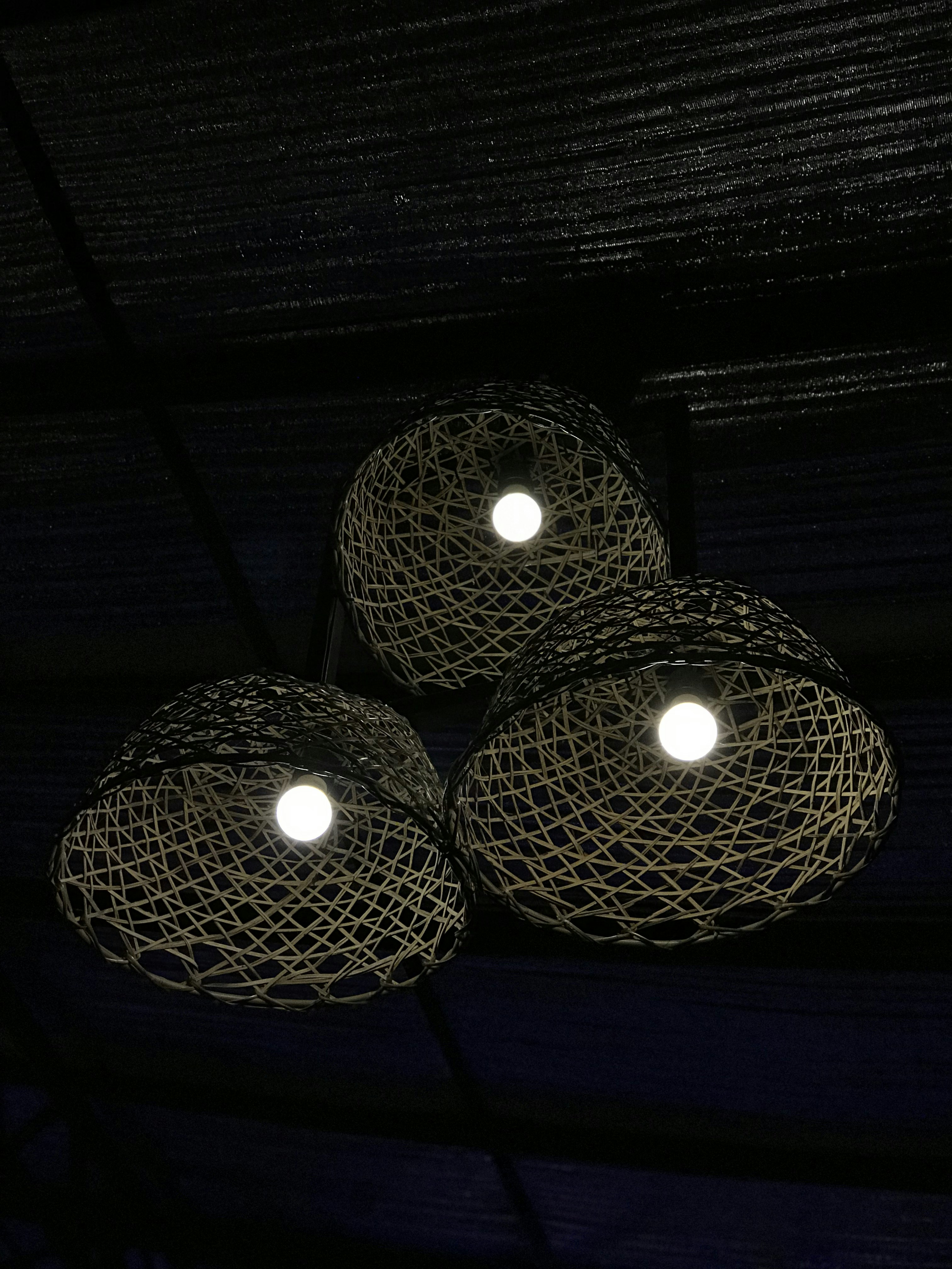 Triad of Woven Pendant Lamps Illuminating a Dark Ceiling