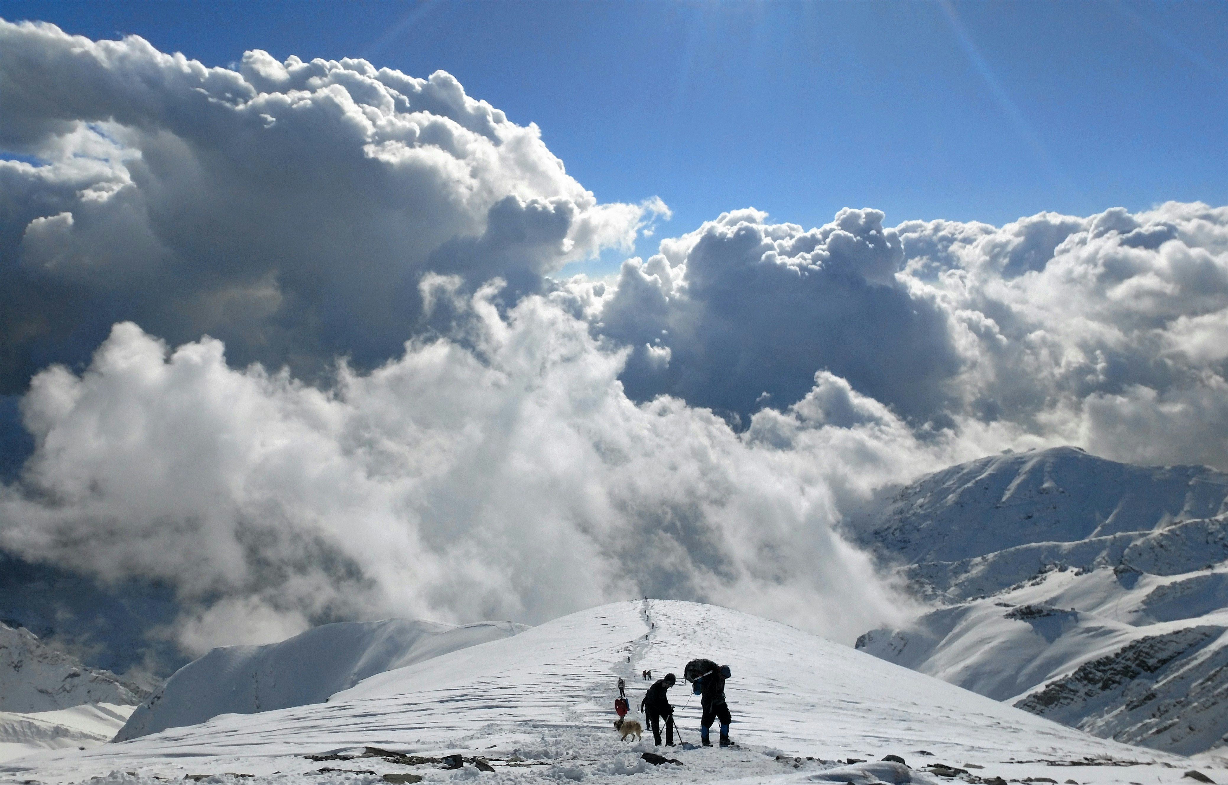 Summit Figures: A Snowbound Climb Beneath Brooding Clouds