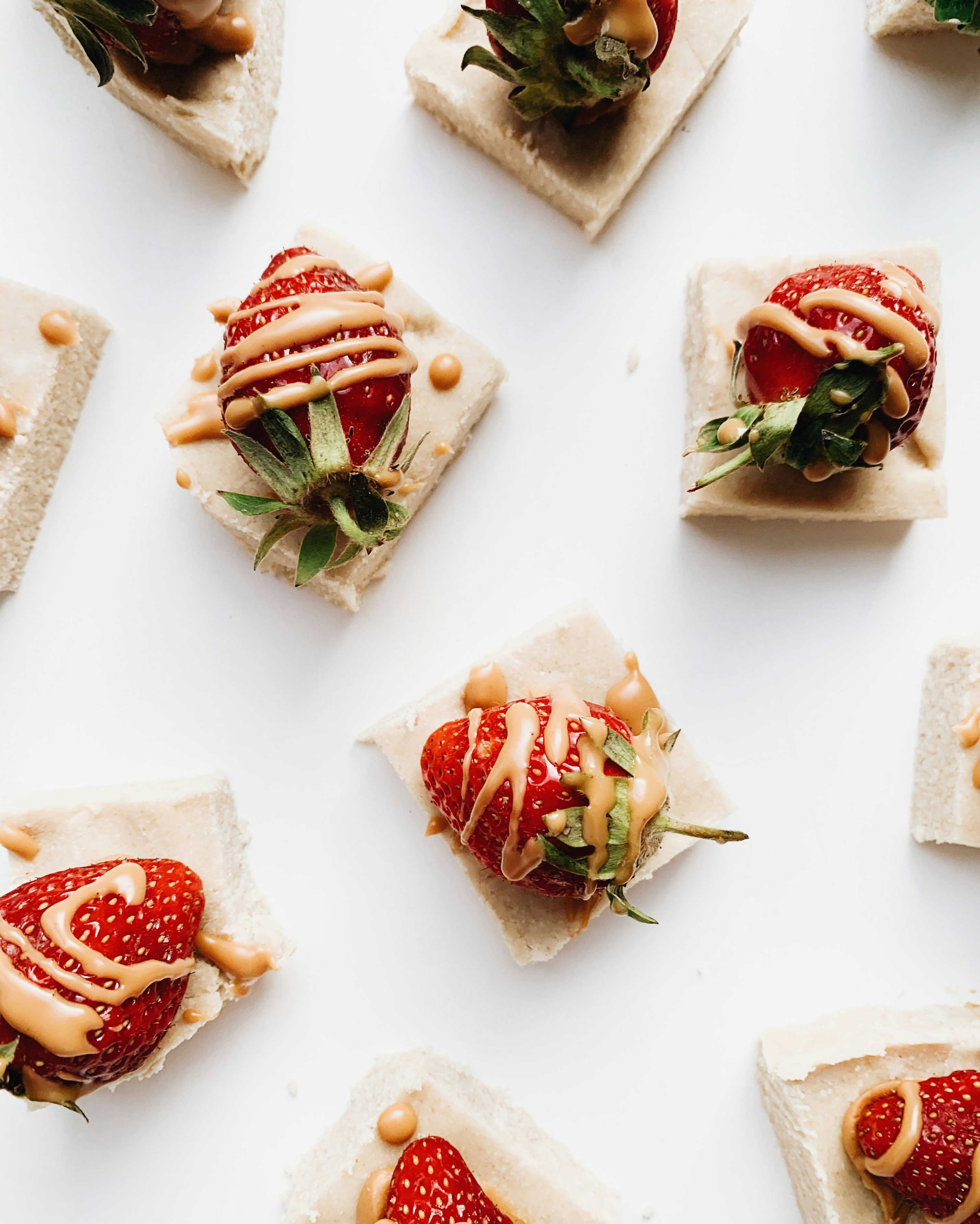 Strawberry Bites on White Canvas: Sweet Squares with Drizzled Cream