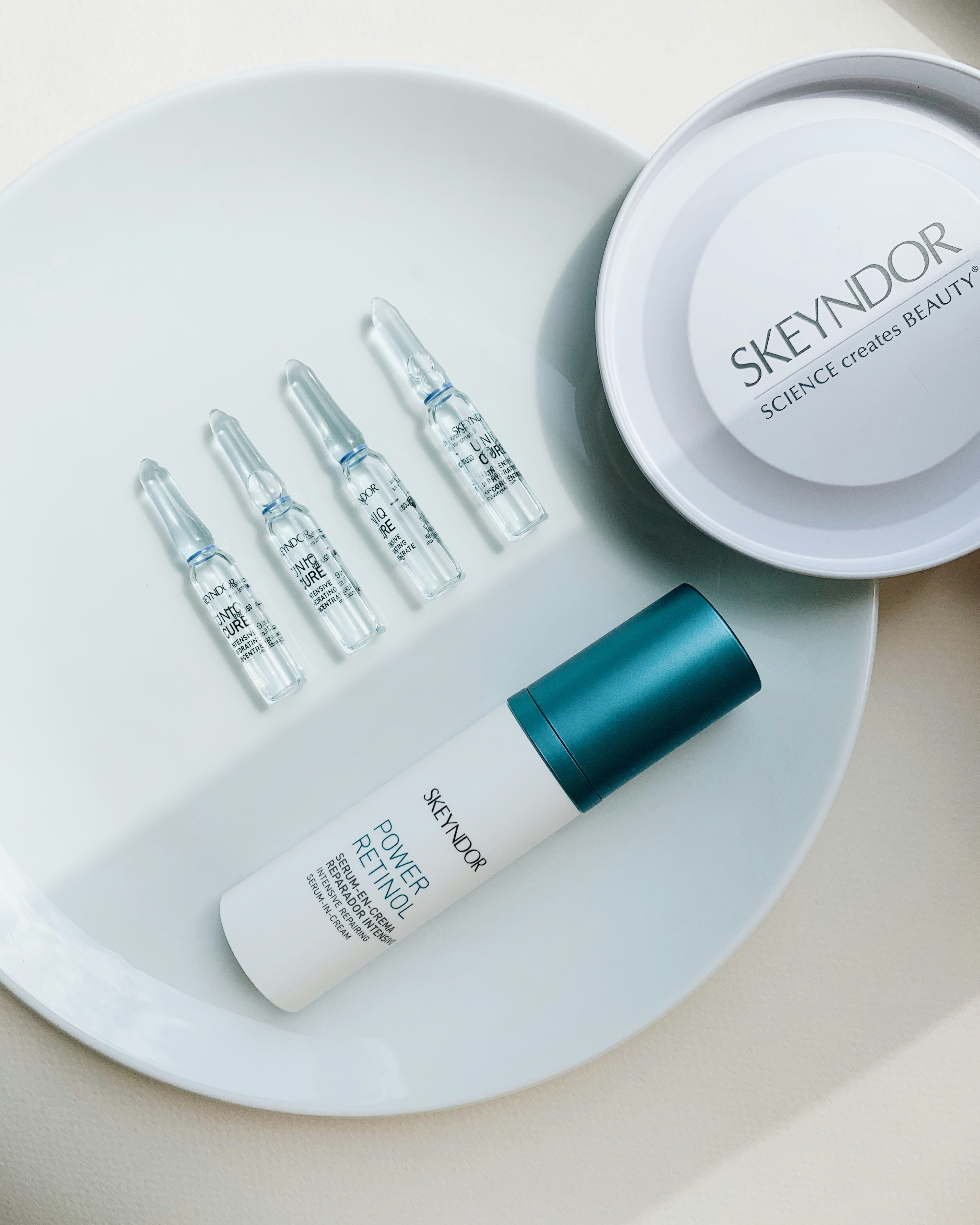 Teal-Capped Serum on a White Plate: A Minimalist Skin-Care Still Life
