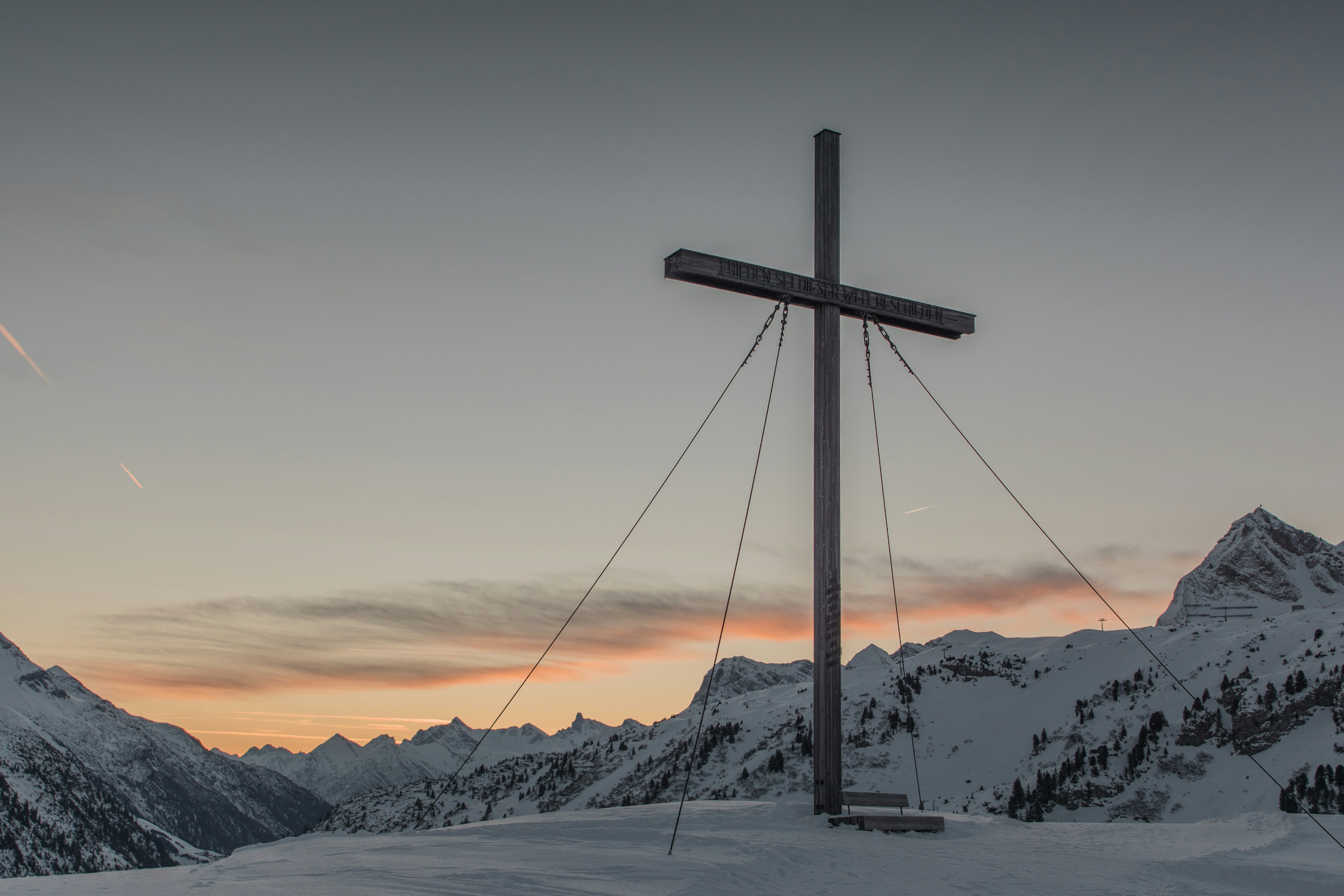 Solitary Alpine Cross Anchored on a Snowbound Ridge at Dusk, Framed by Alpine Peaks