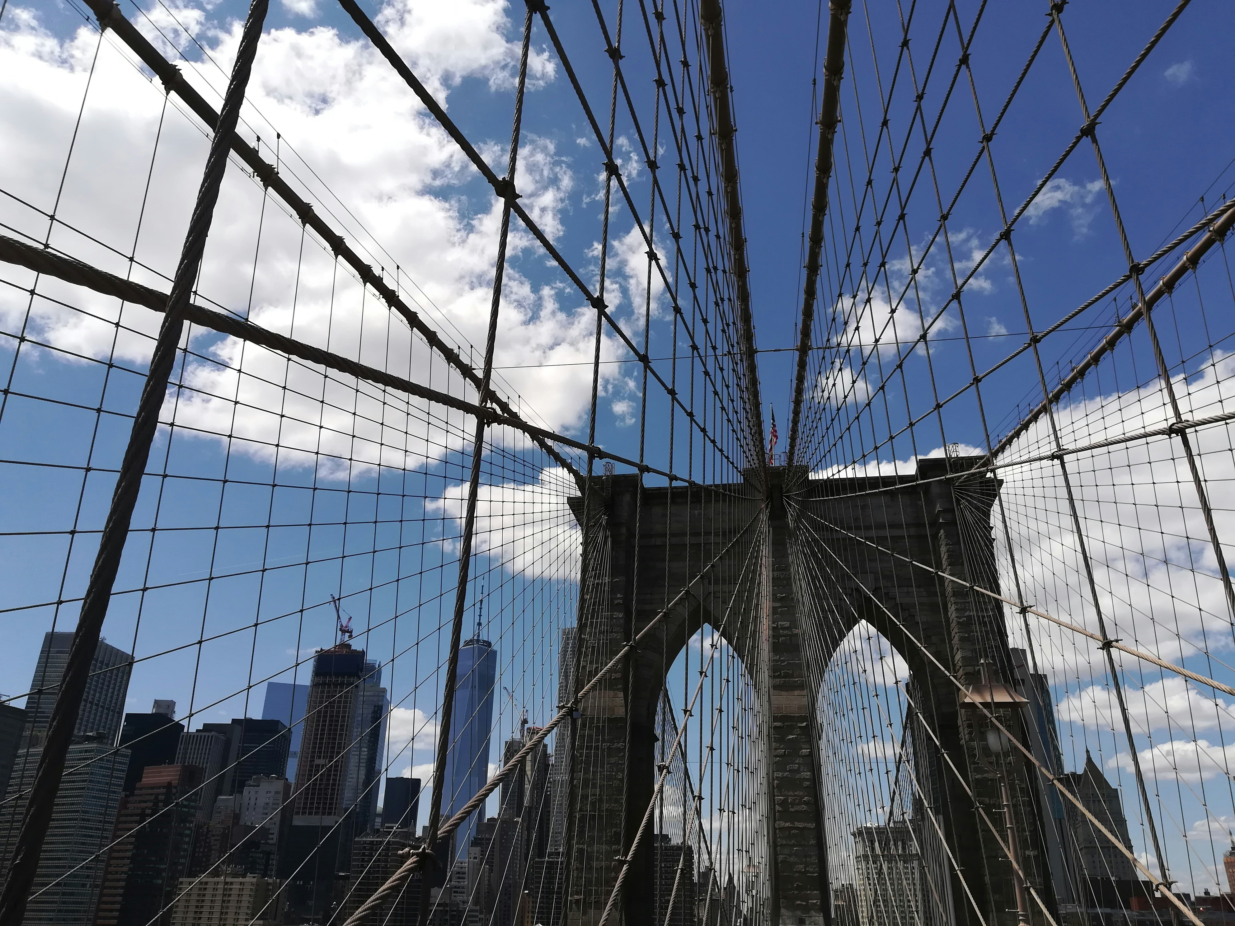 Brooklyn Bridge's intricate cable network against a backdrop of skyscrapers and a vibrant sky.