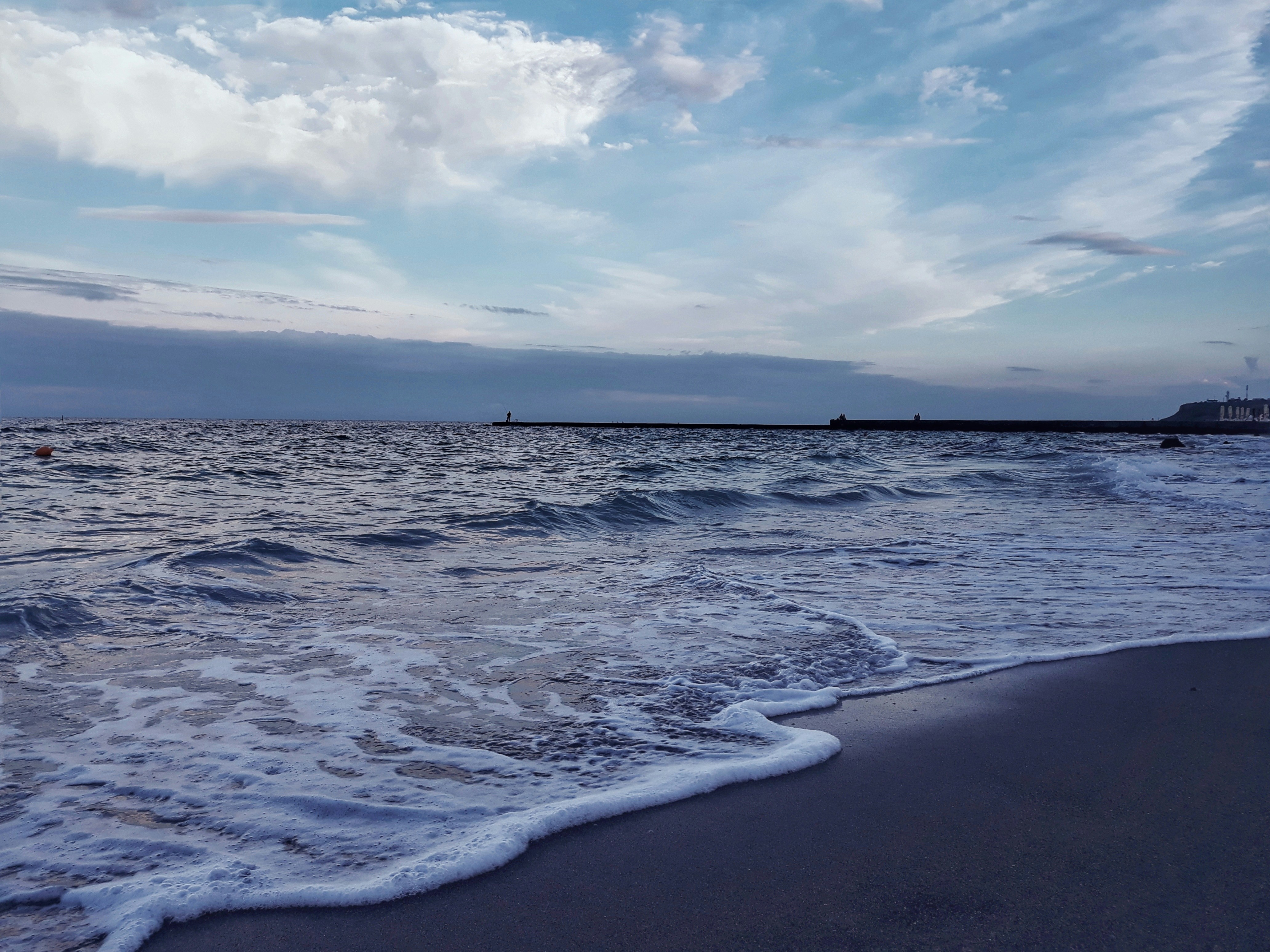 Gentle waves lapping at the shore under a moody sky, capturing the serene transition from day to night.