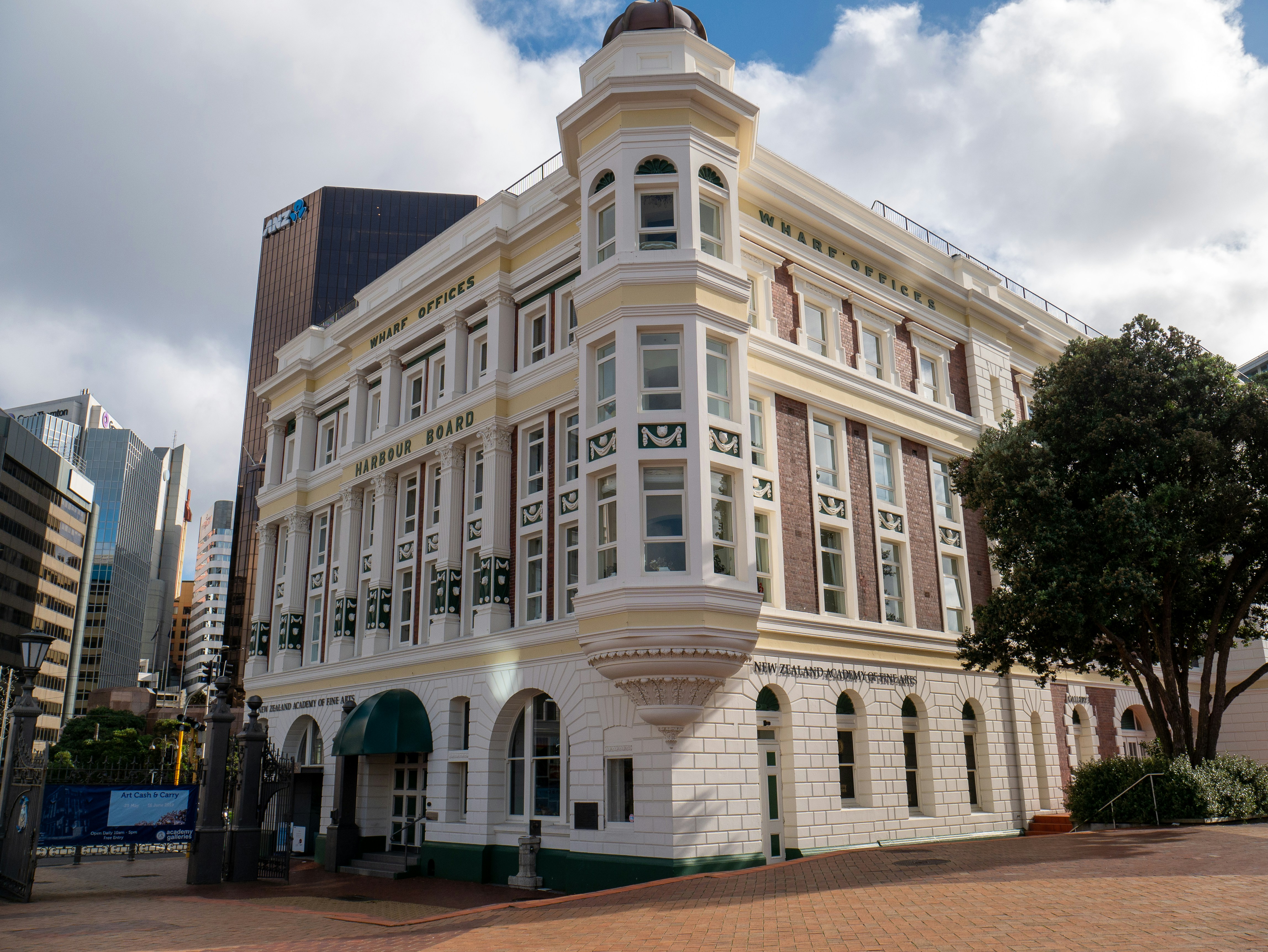 Ornate white building with classical details stands against a backdrop of modern skyscrapers under a partly cloudy sky.