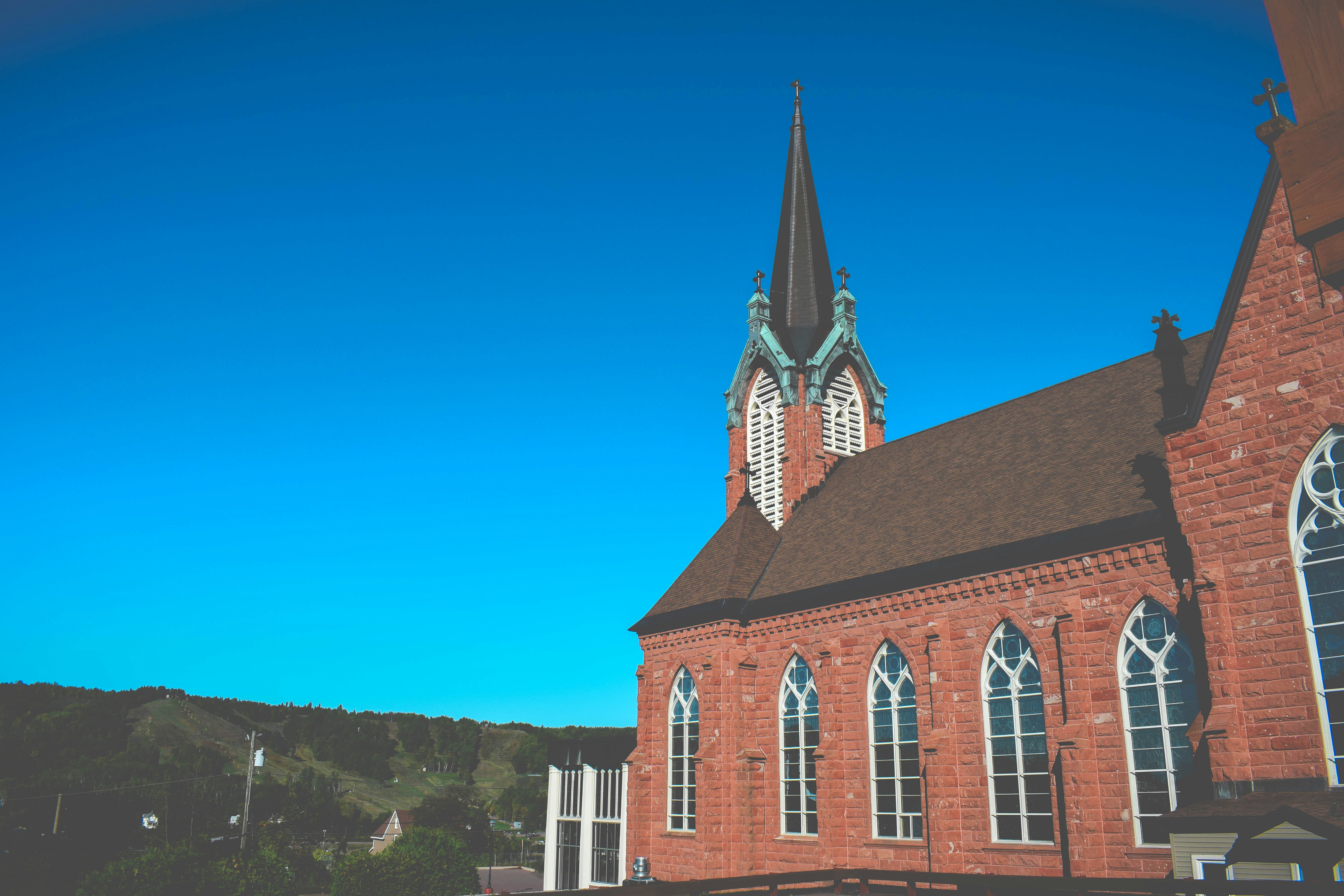 Historic church with intricate stained glass windows and a tall spire, set against a vibrant blue sky.