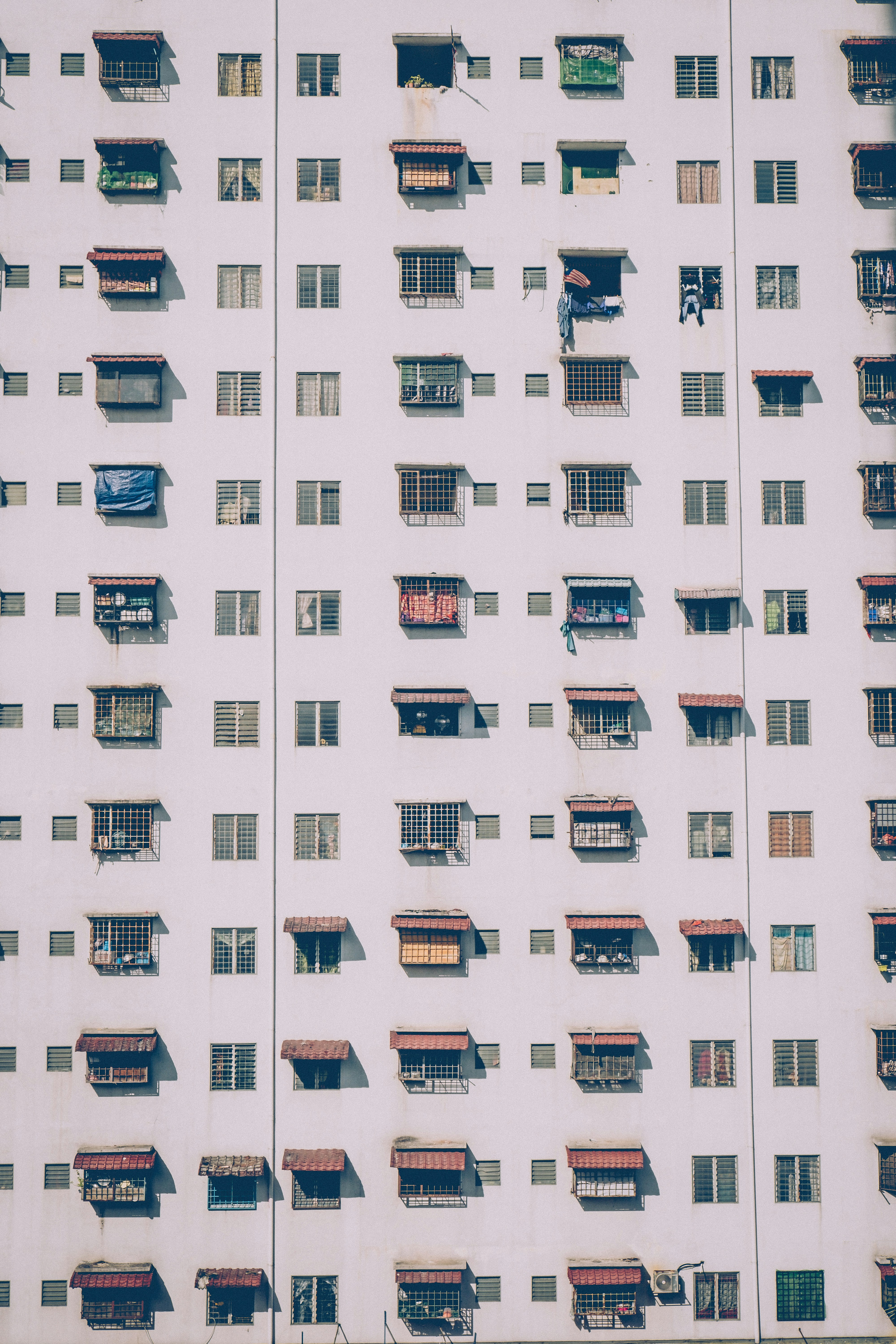 A close-up view of a residential building's facade, showcasing a grid of balconies and windows with various colors and textures.
