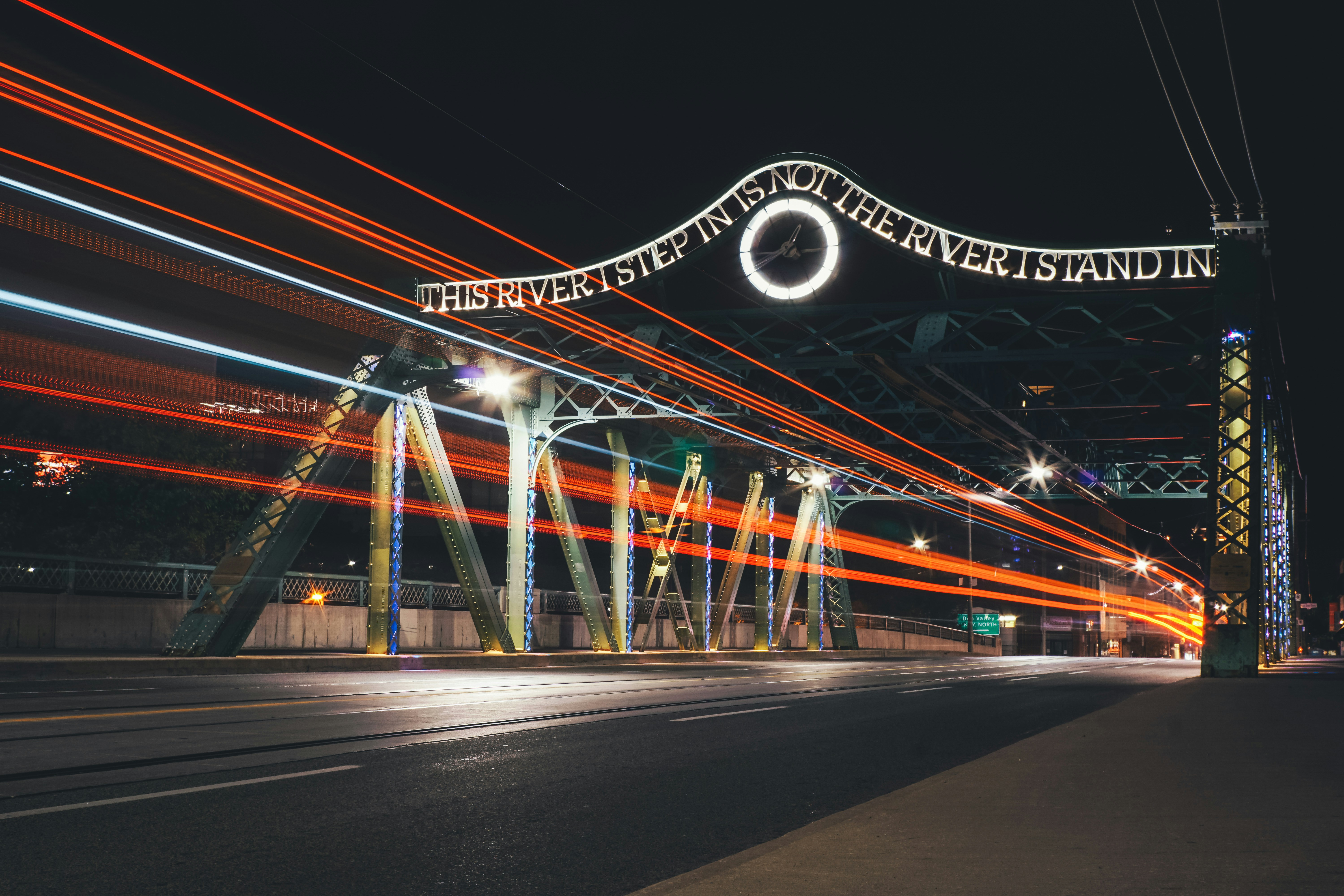 Neon Arch Over River Road: A Nighttime Long-Exposure in Motion