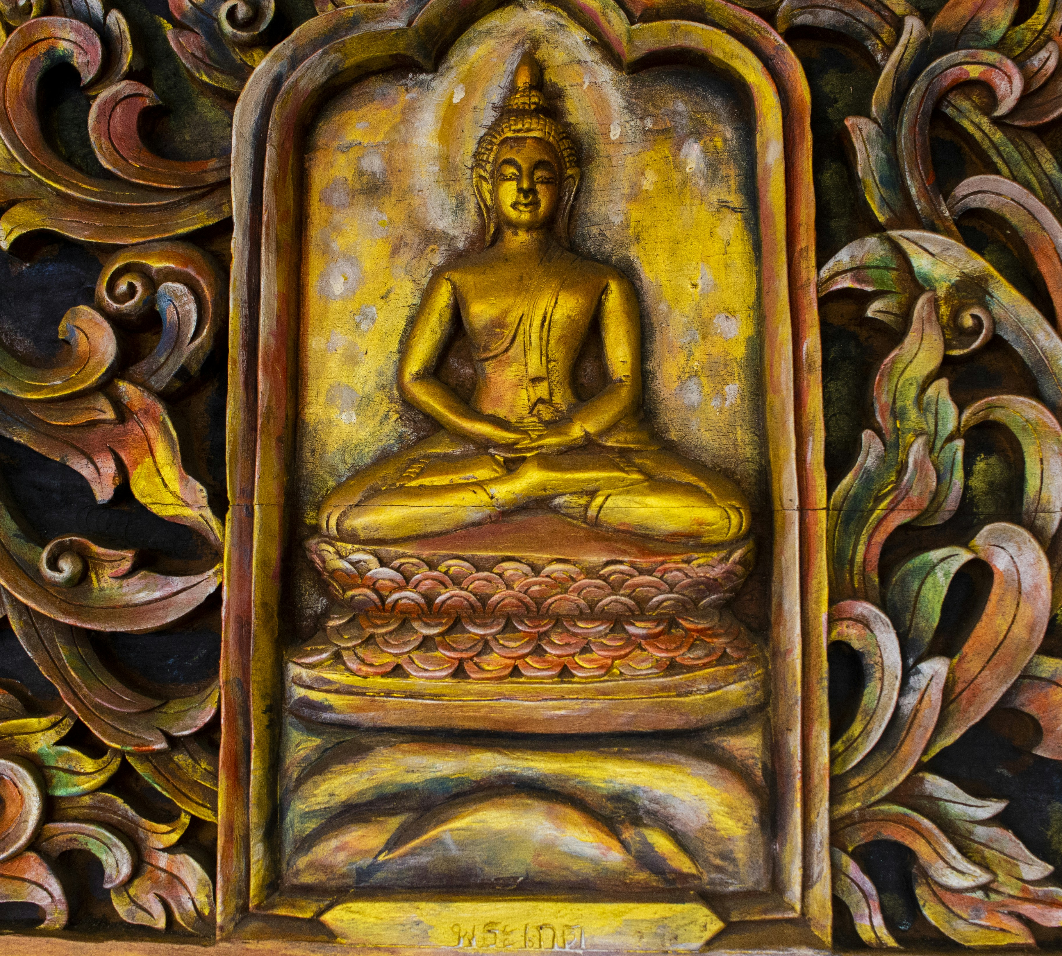 Intricately carved wooden Buddha surrounded by swirling patterns in warm tones.