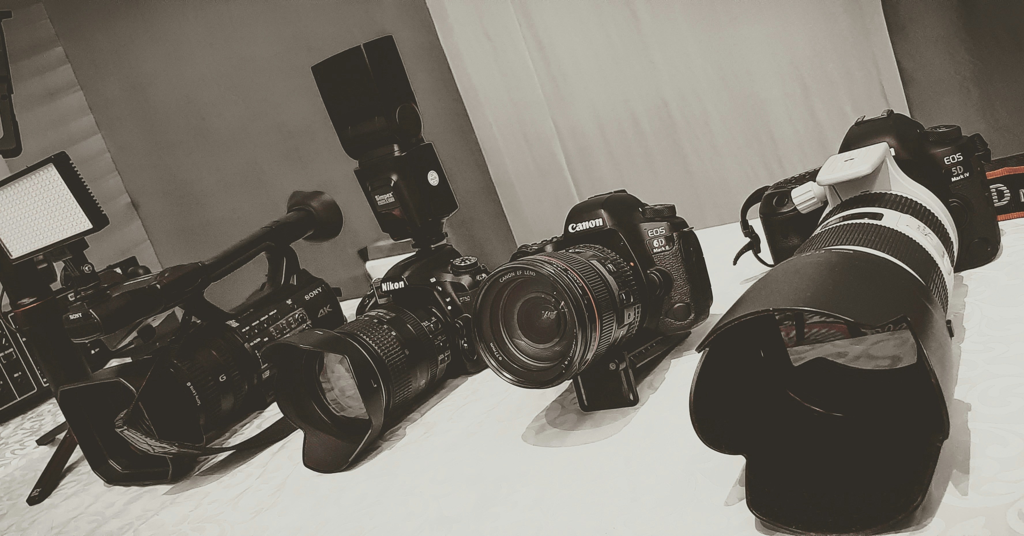 Black and white image showcasing an array of professional camera equipment on a table.