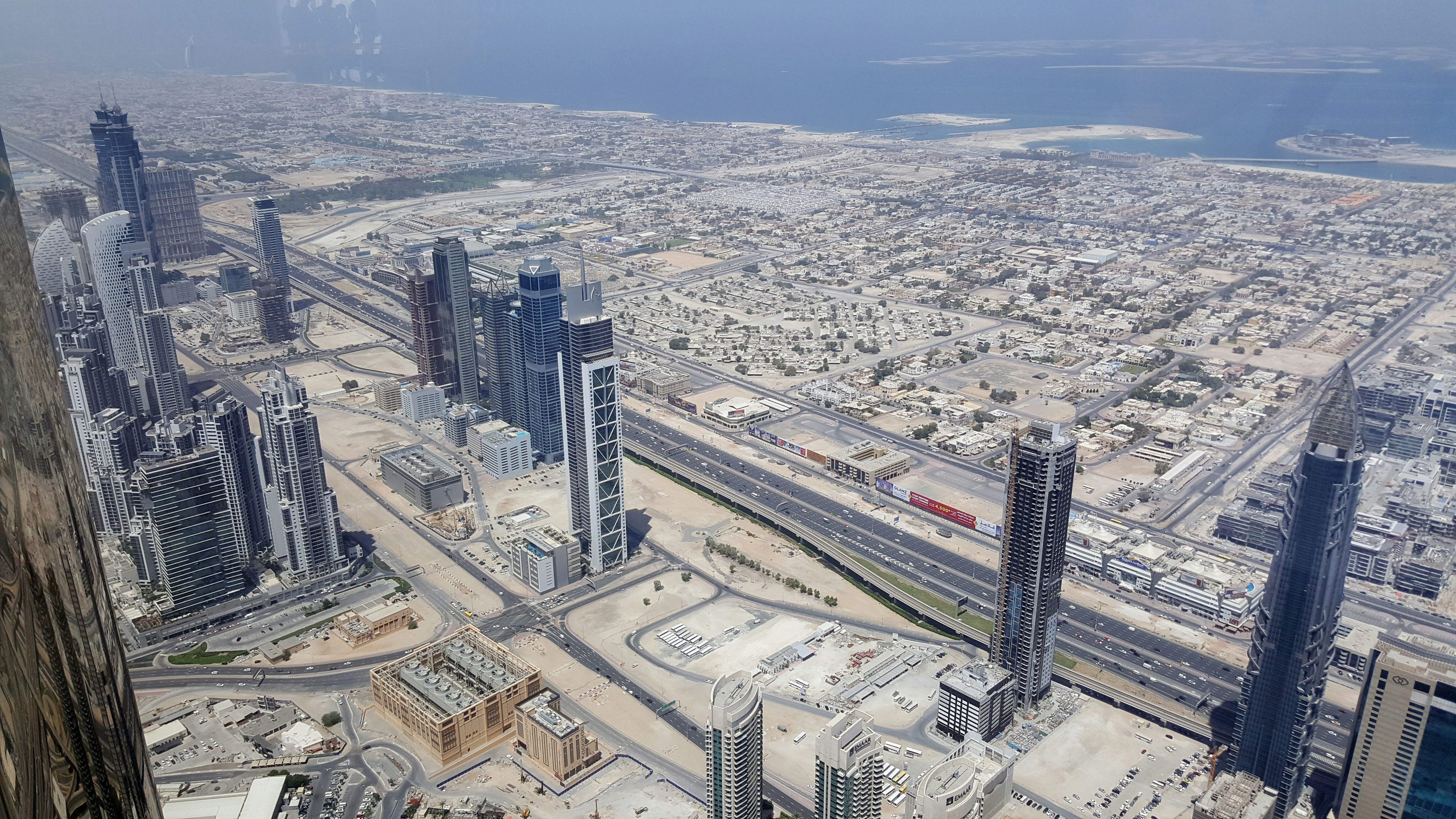 Aerial view showcasing a sprawling urban landscape with towering skyscrapers and a bustling highway, highlighting the contrast between architecture and the desert terrain.