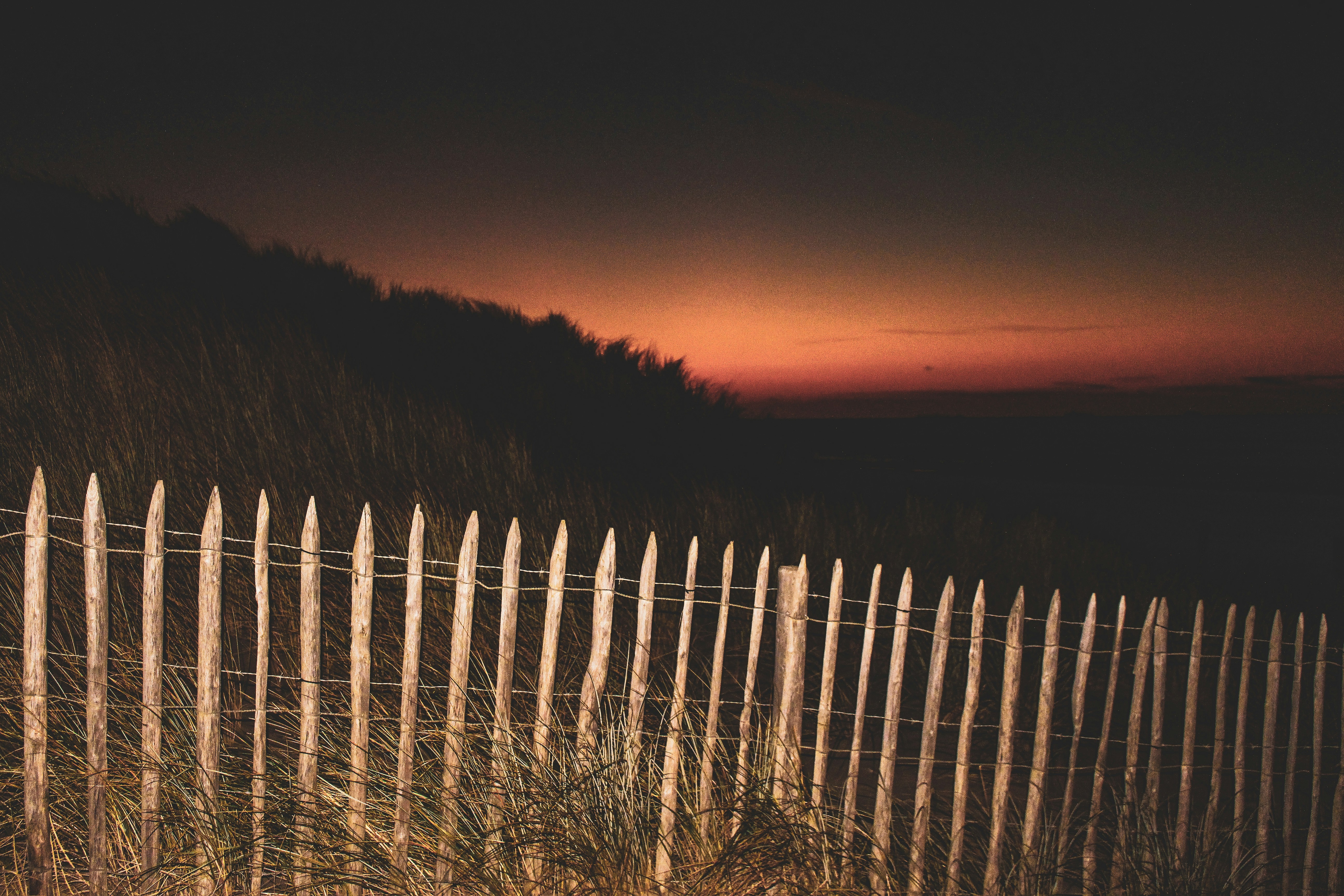 silhouette photo of brown fence and green grass fields