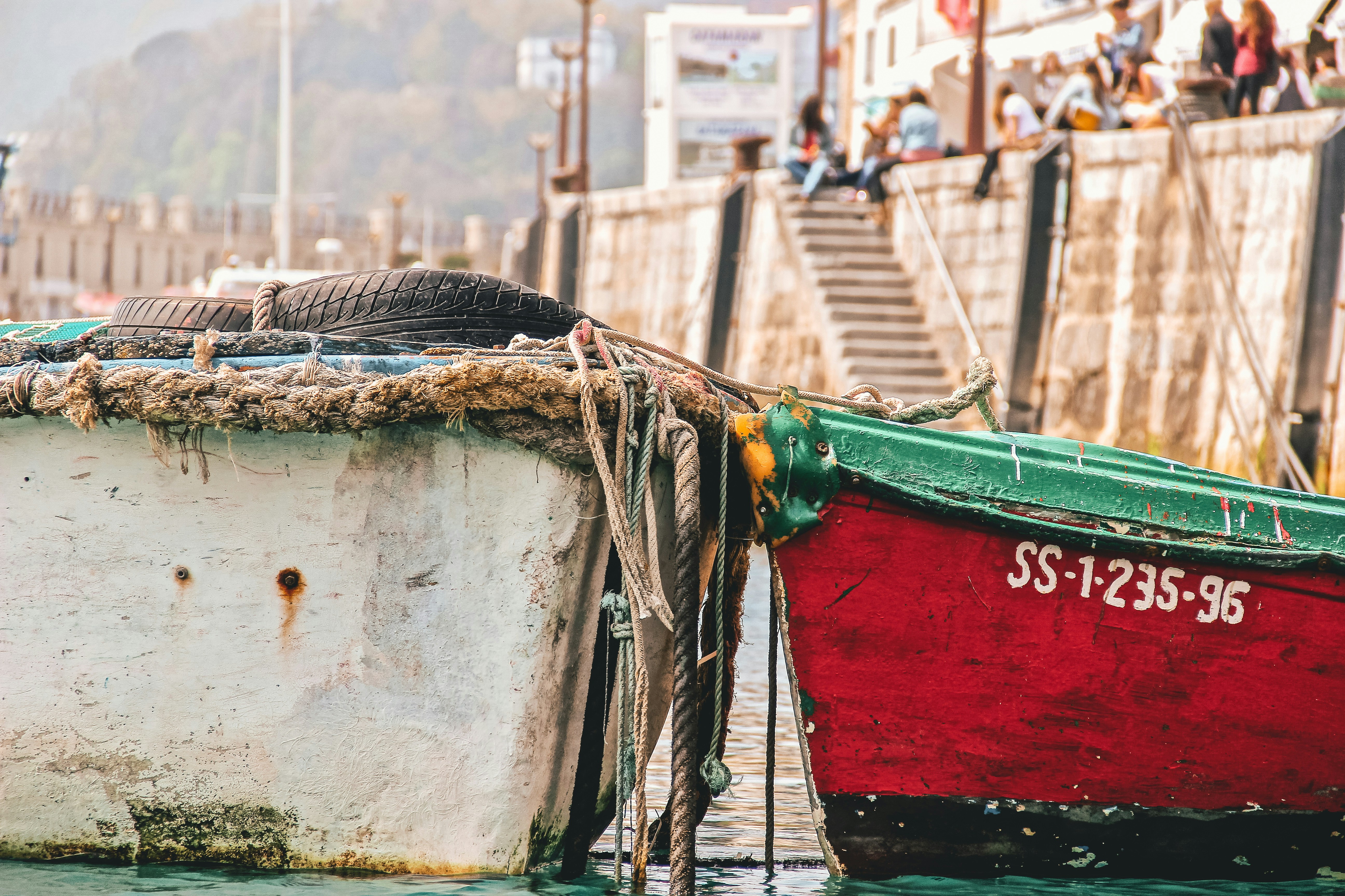 Two boats on sea near people standing and walking beside pathway photo ...