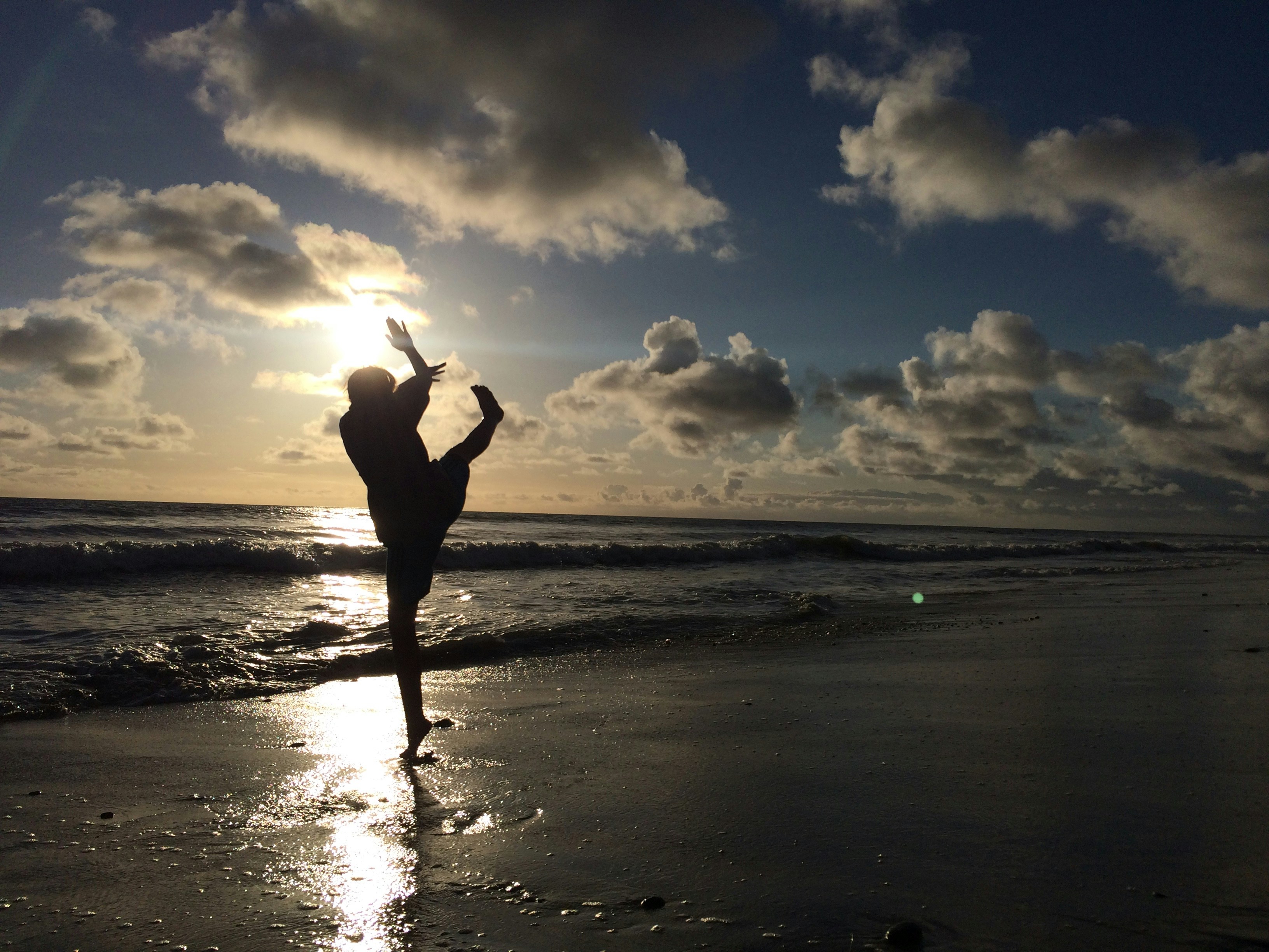 Sunlit Silhouette: A Dancer on the Shoreline at Dusk