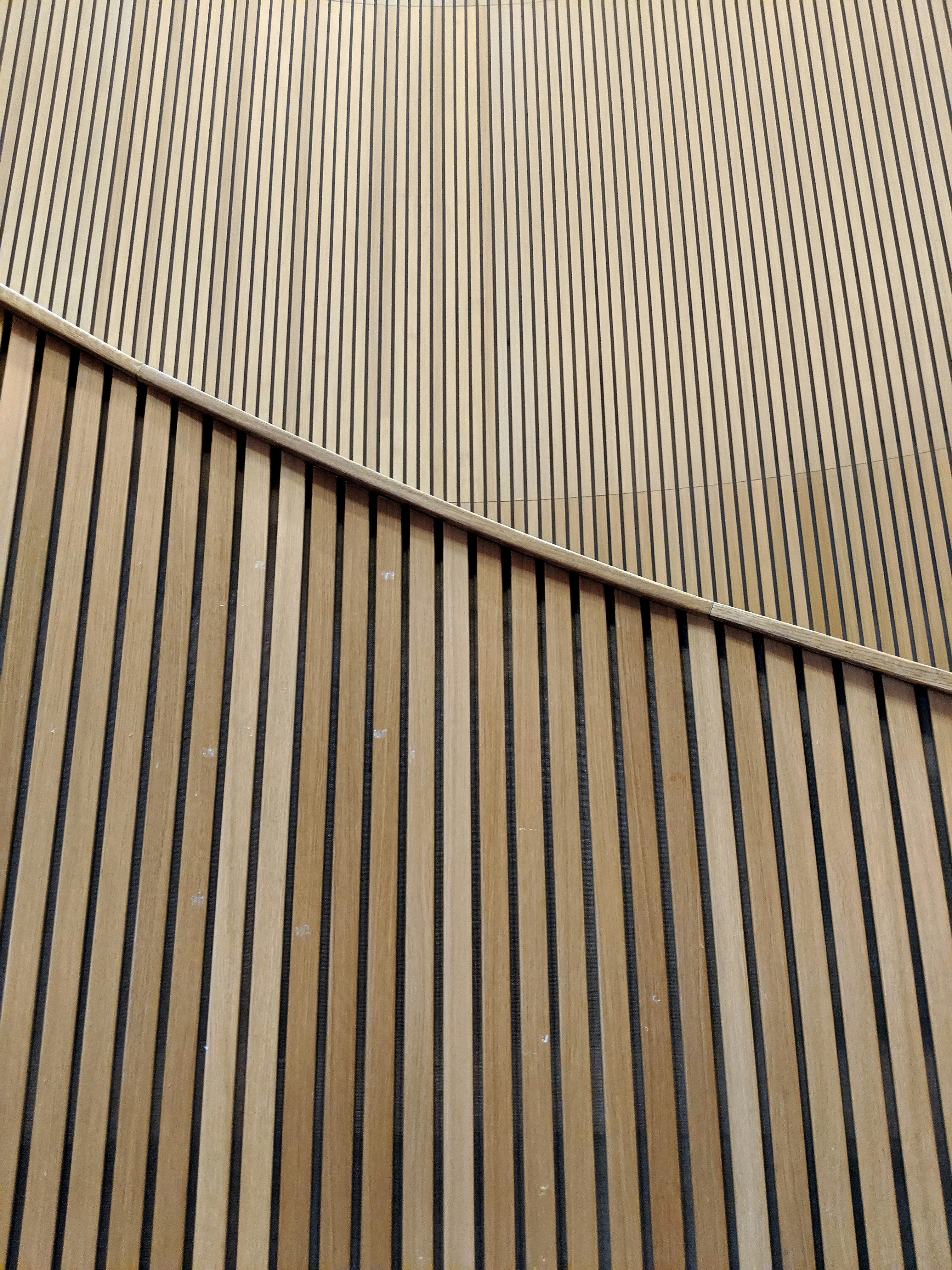 Close-up of a wooden surface featuring alternating light and dark stripes, creating a rhythmic pattern. The design emphasizes the natural grain and craftsmanship.