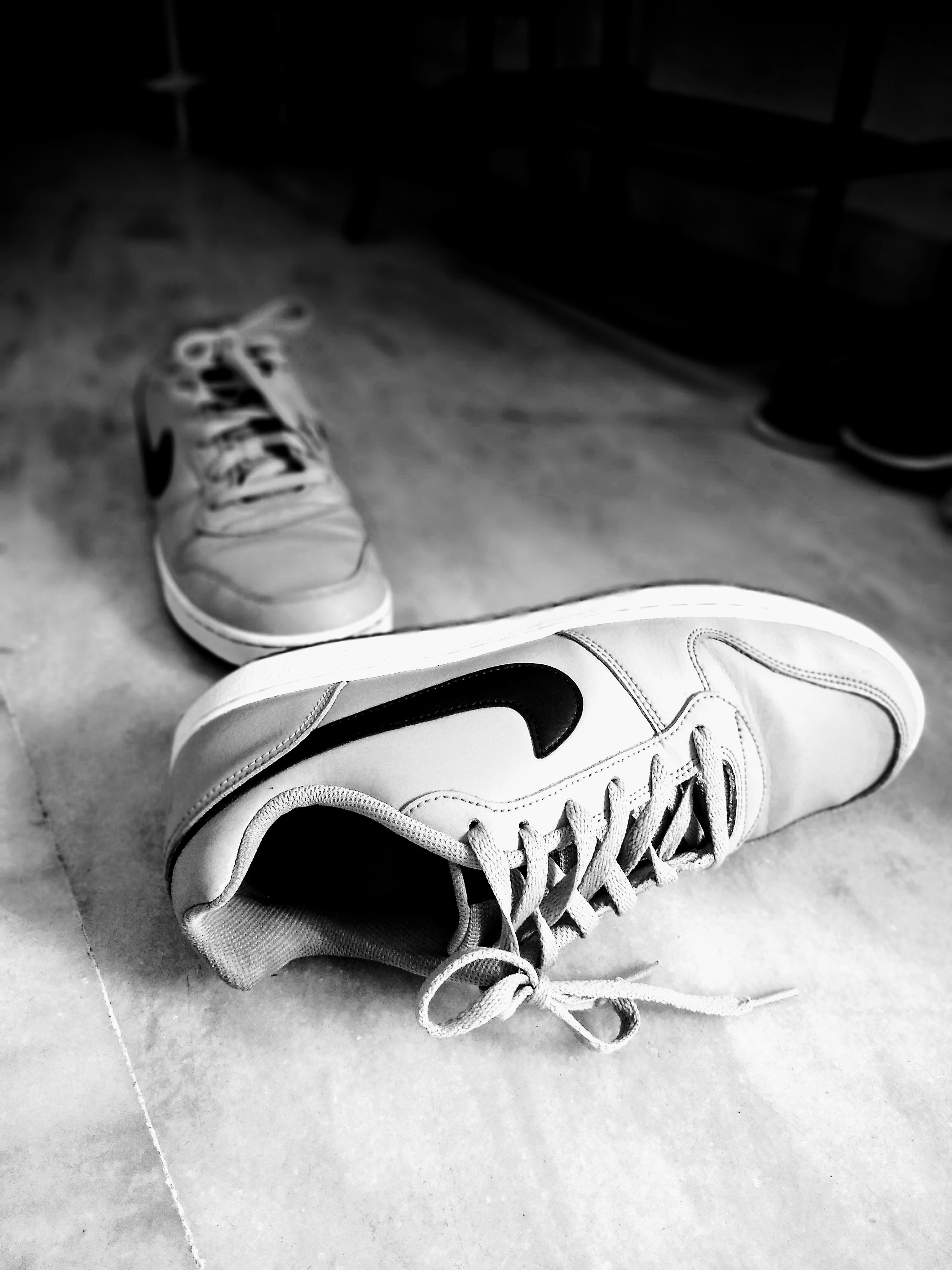 Close-up of a pair of Nike sneakers in a monochrome setting, showcasing texture and detail against a simple background.