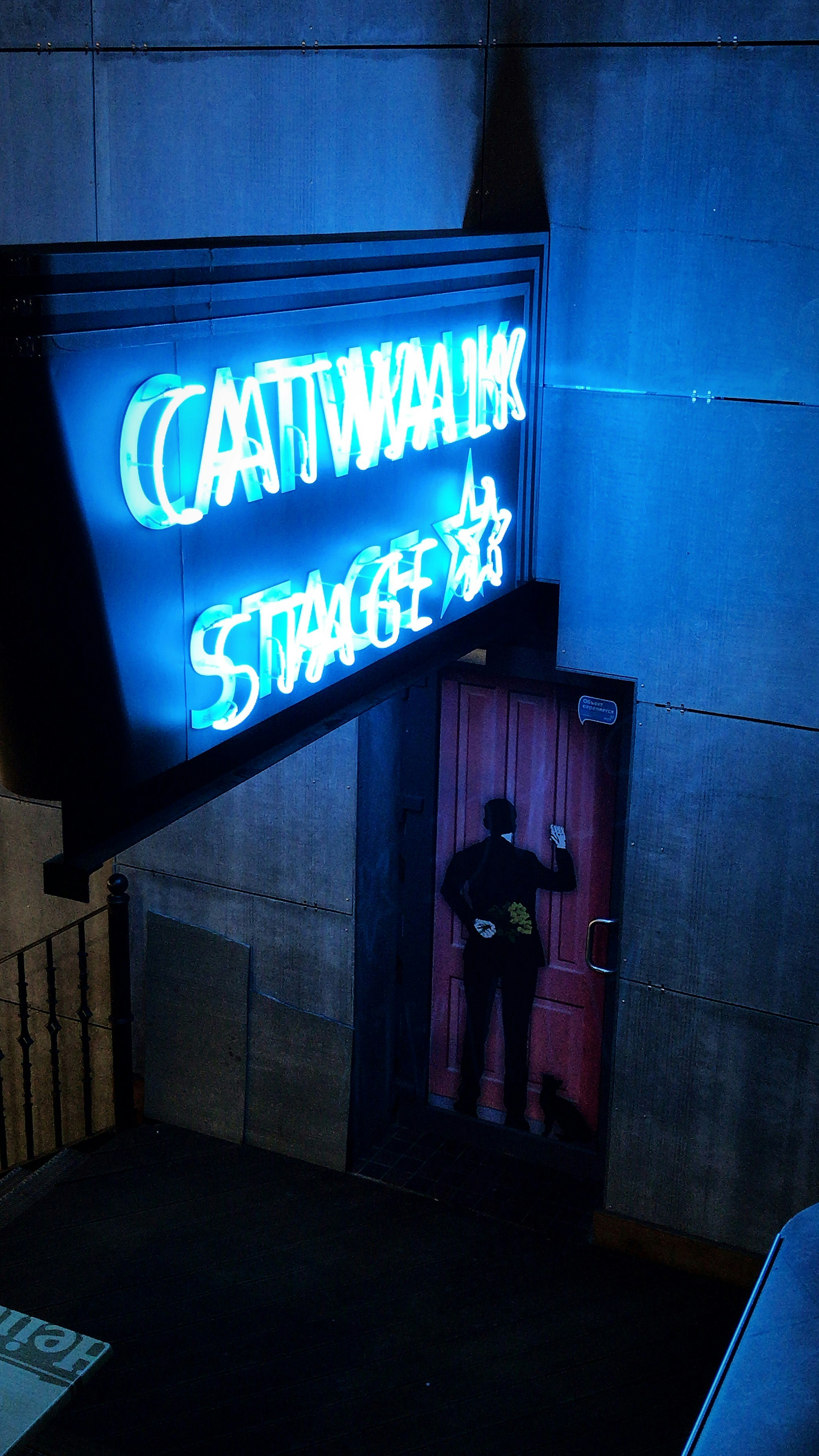 Blue Neon Catwalk Sign Over a Backstage Door