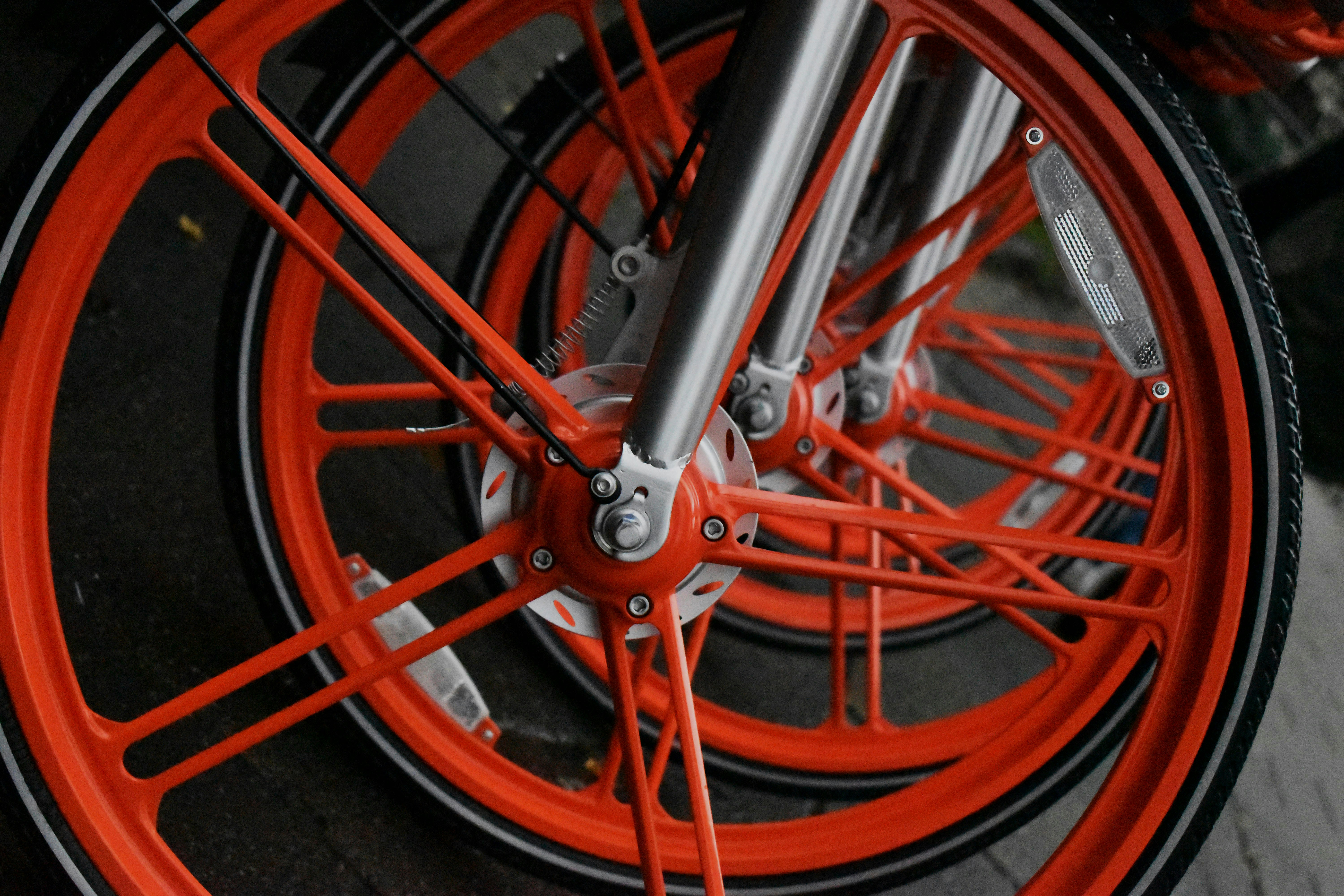 Close-up view of vibrant orange bicycle wheels showcasing intricate spoke design and metallic components.