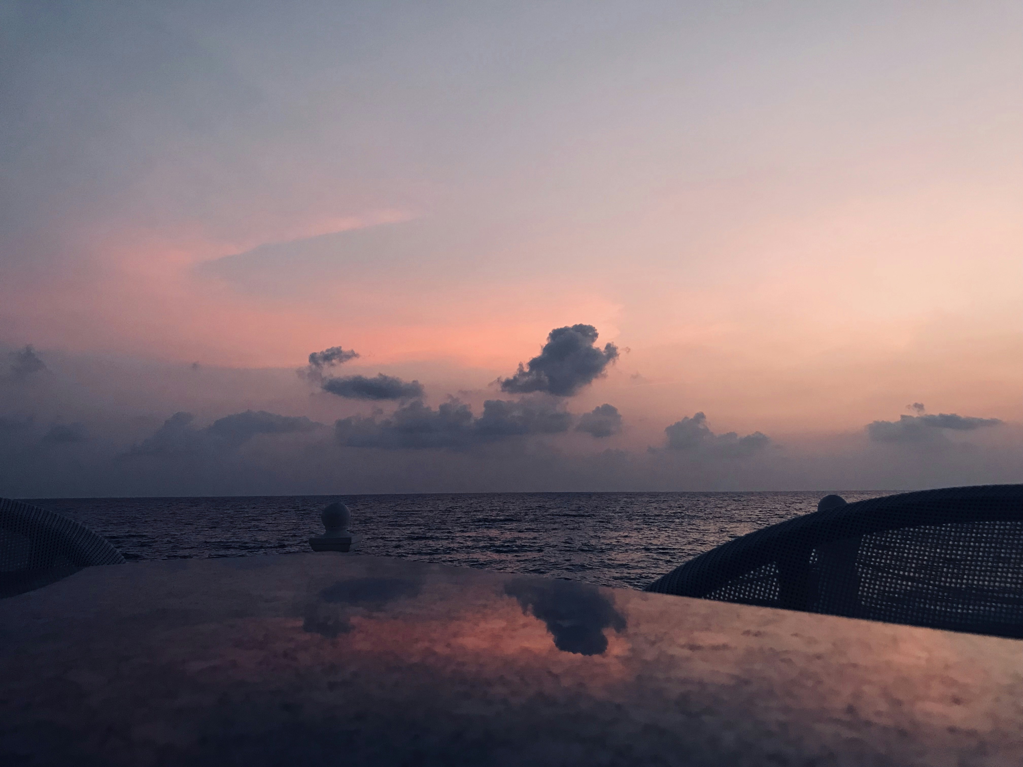 Serene sea view with pastel clouds reflected on a glossy surface at dusk.