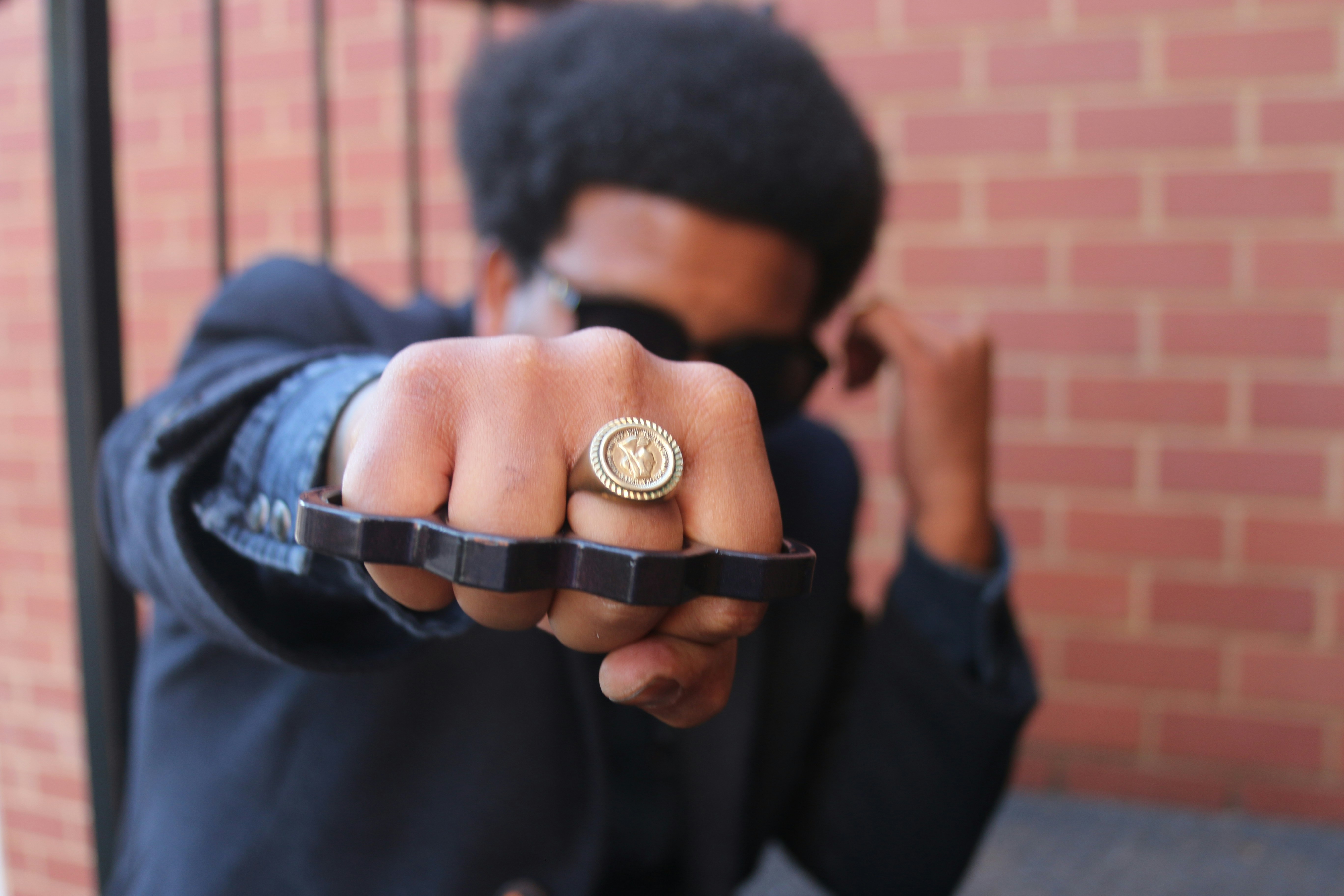 Close-Up of a Fist with a Blurred Masked Figure in Background