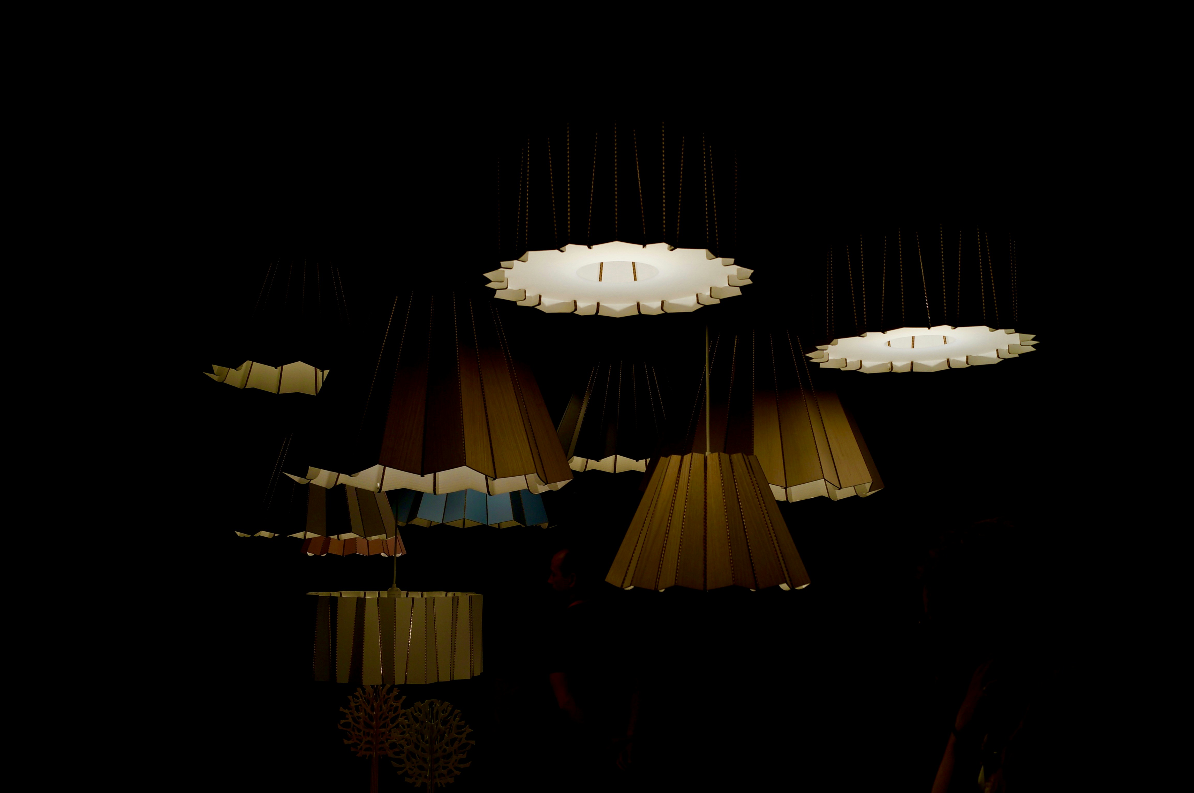 A collection of uniquely designed lamps suspended in a dark setting, showcasing their intricate shapes and soft illumination.