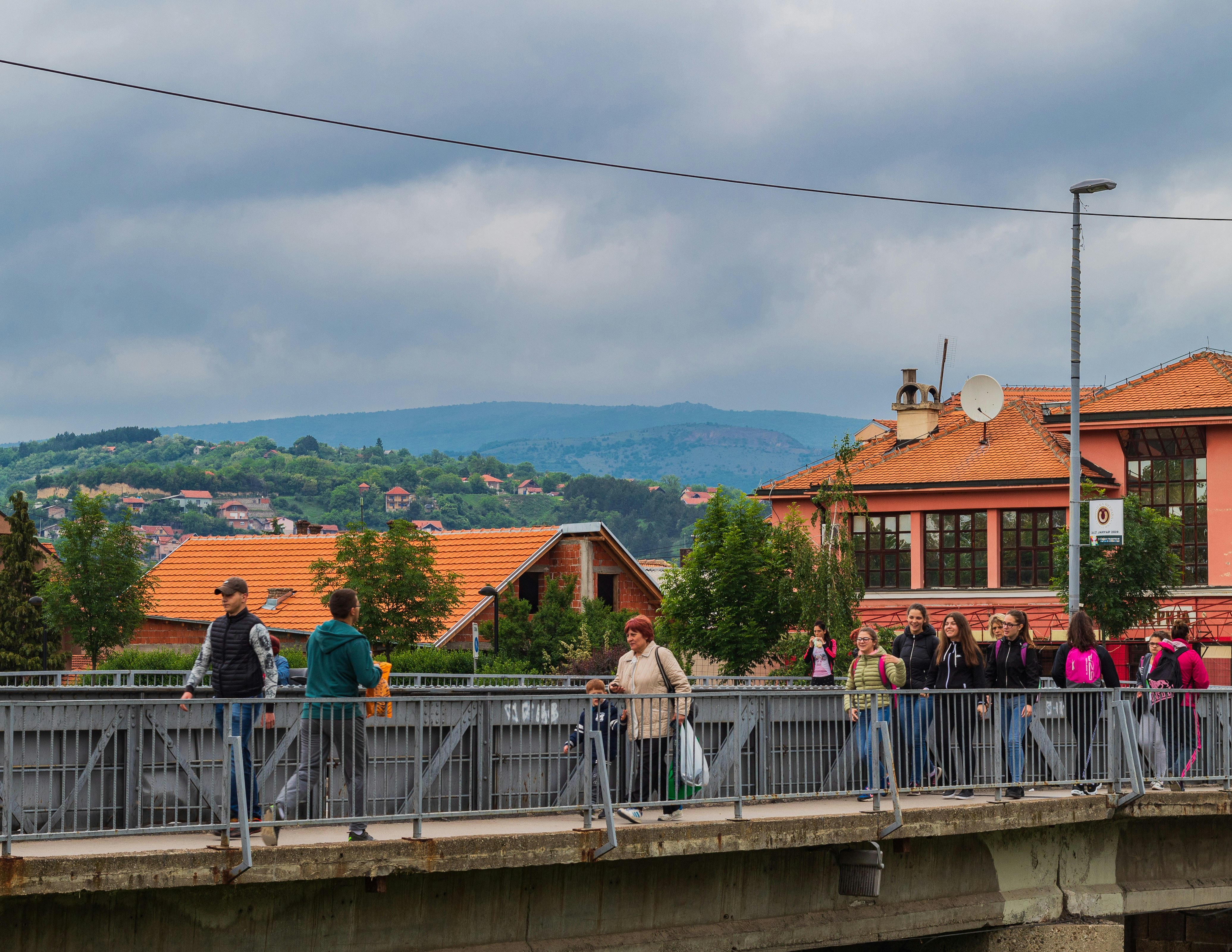 Bridge Walkers Over an Orange-Tiled Town