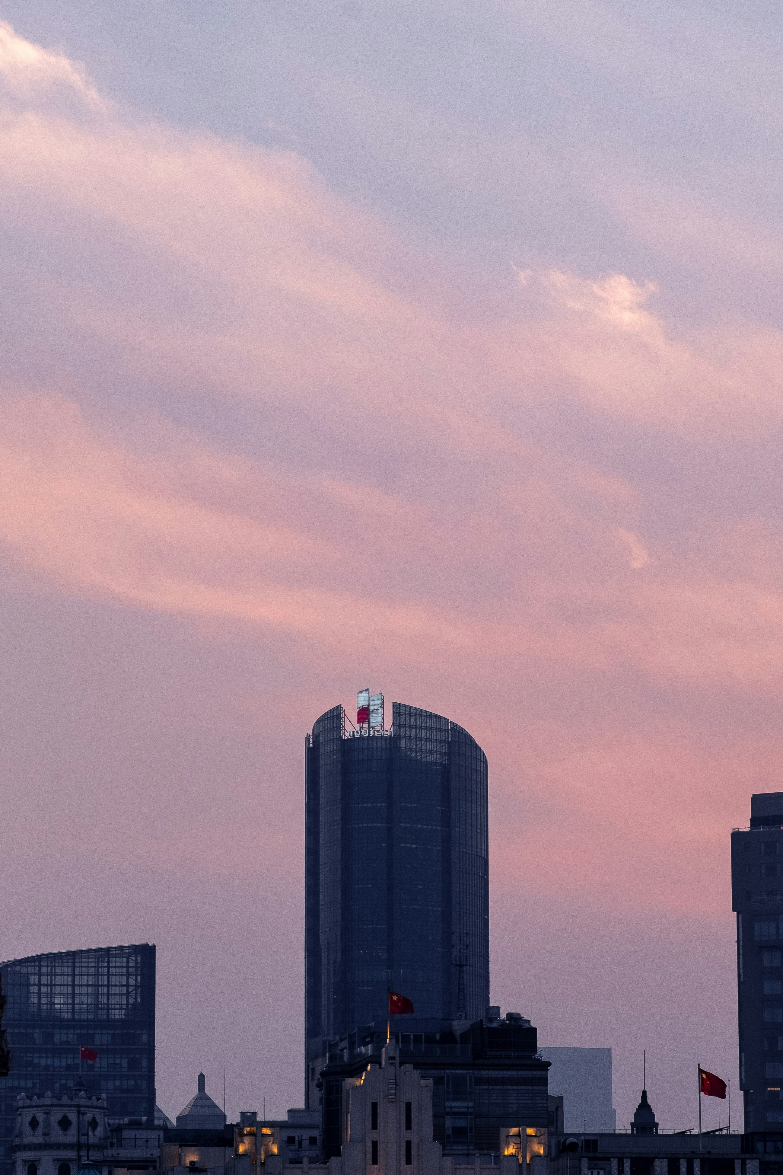 City skyline at dusk featuring modern skyscrapers with a soft pastel sky backdrop. The scene captures the essence of urban life transitioning into evening.