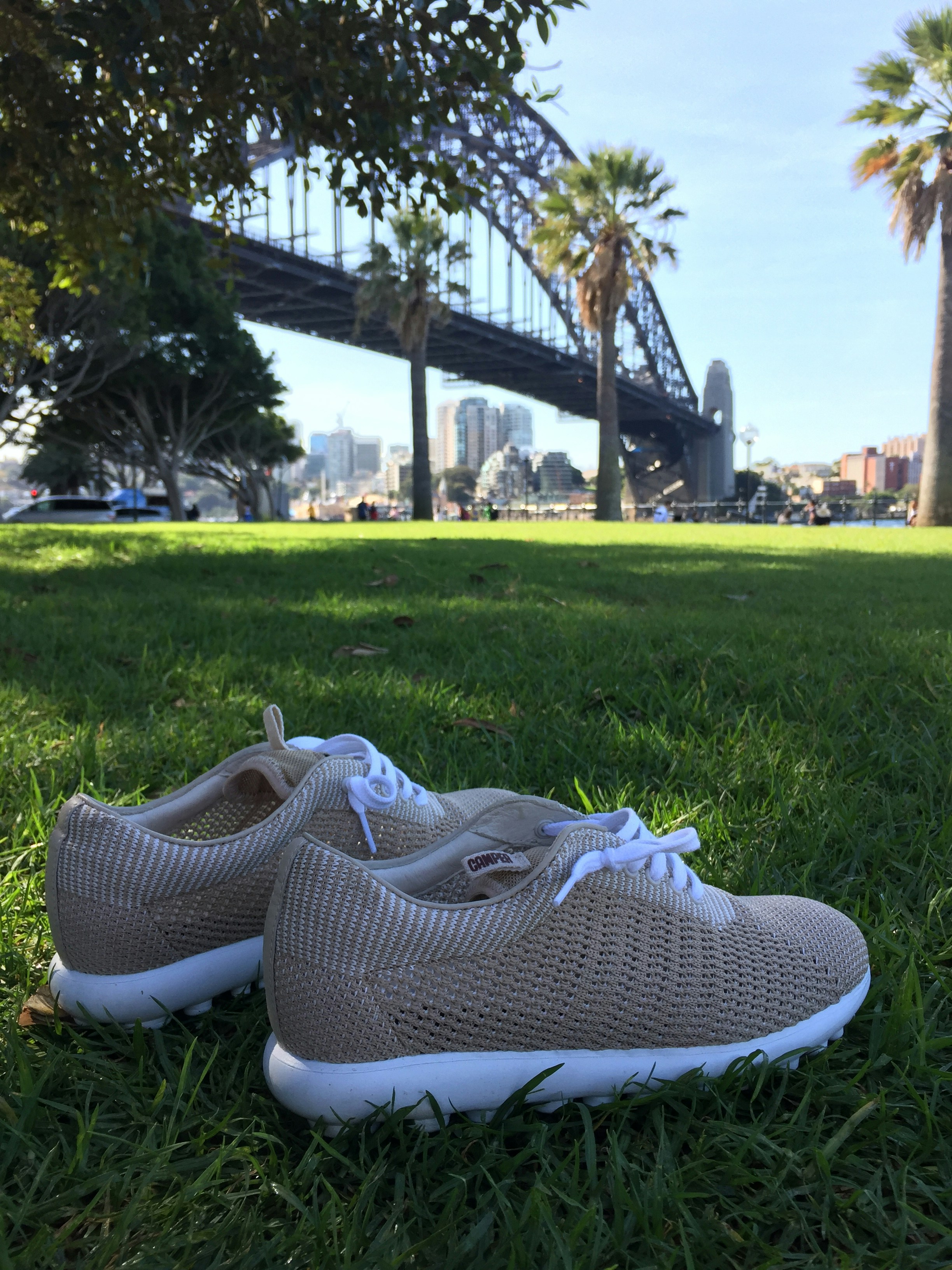 Ground-Level Muse: Beige Sneakers with a City Bridge Backdrop