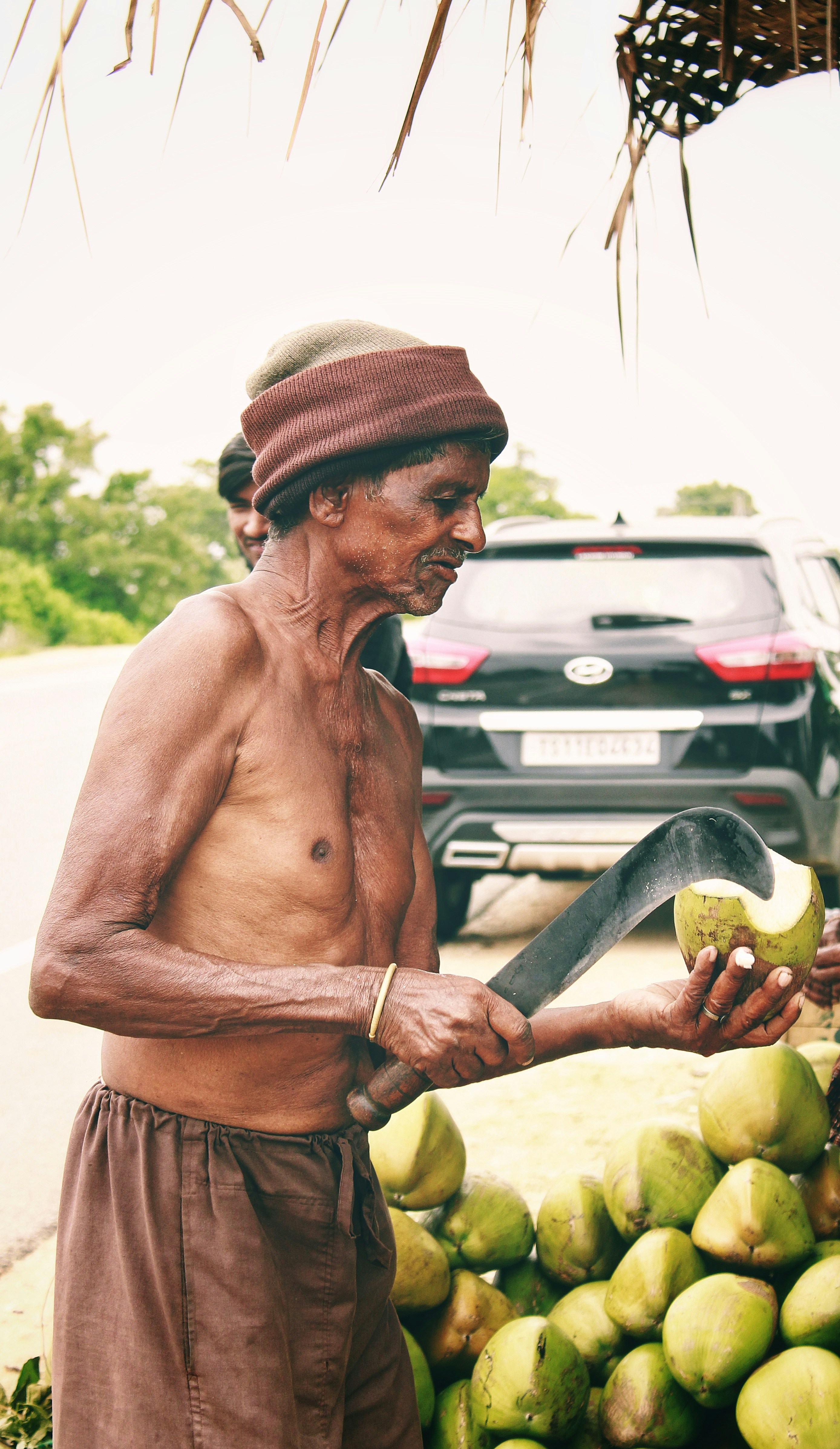 Roadside Coconut Cutter: Labor Under Palm Shade