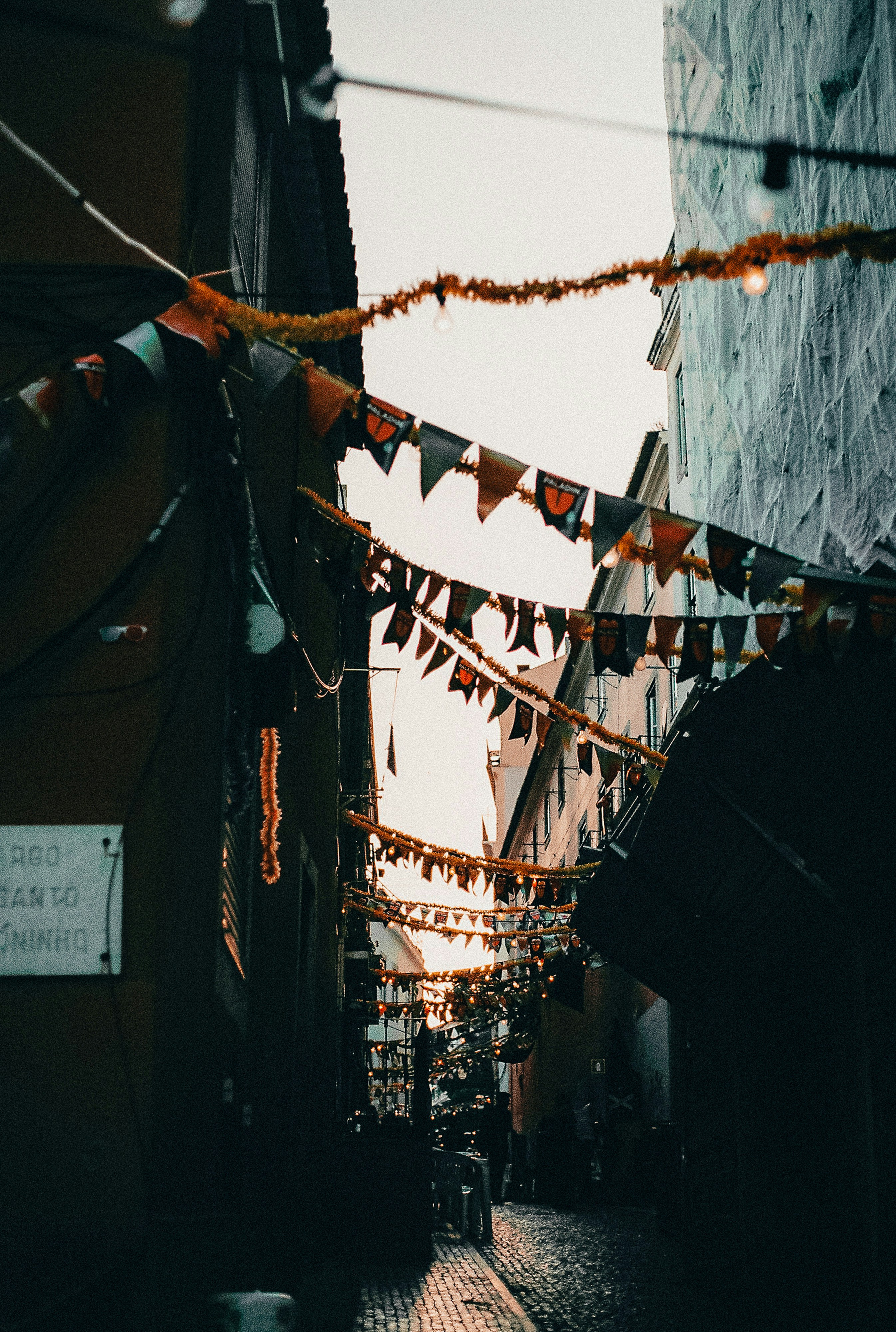 Dusk in the Festive Alley: Flags Spanning a Narrow Cobblestone Way