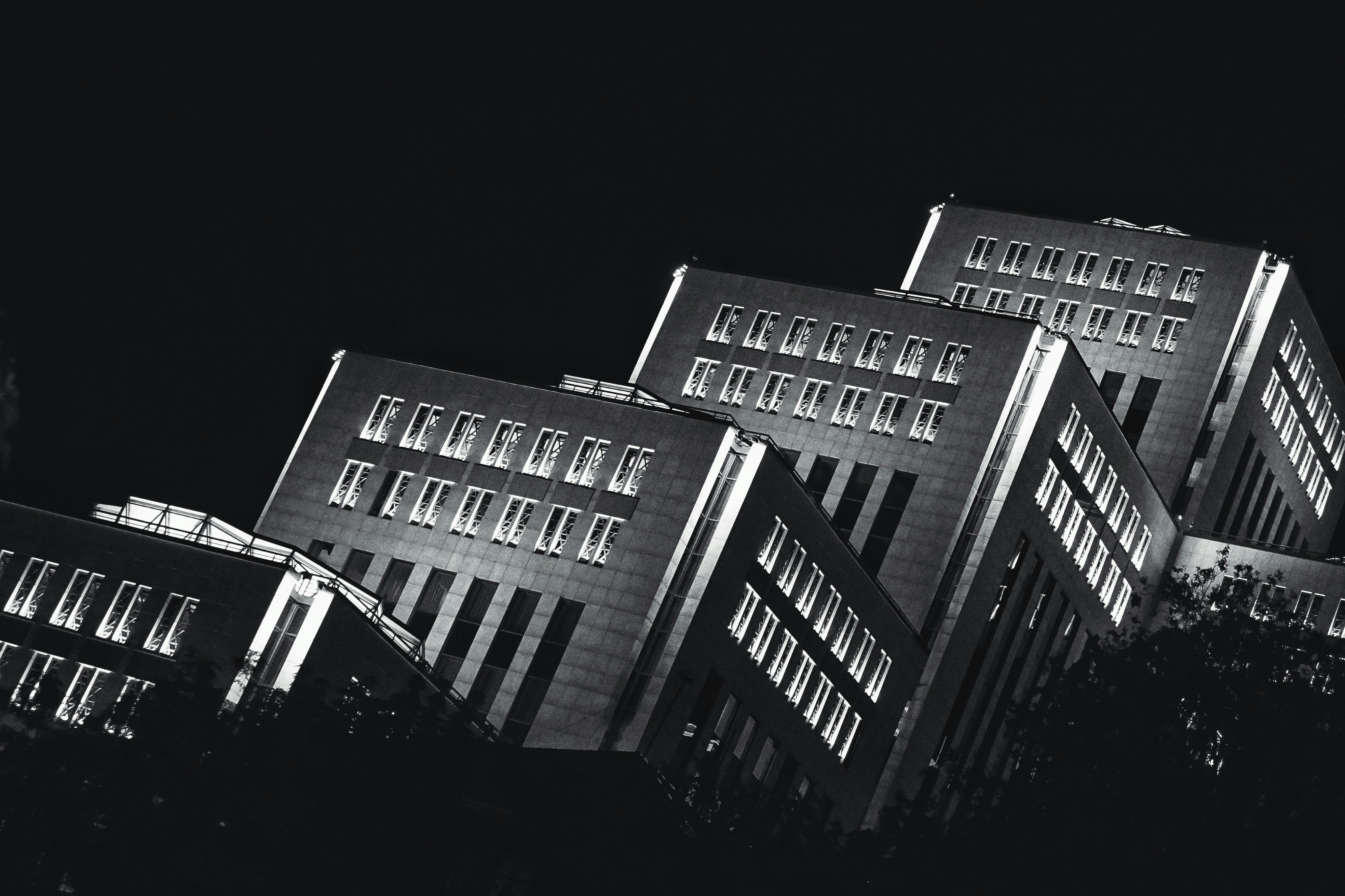 Geometric buildings stacked in a dramatic angle, illuminated against a dark backdrop, showcasing modern architectural design.