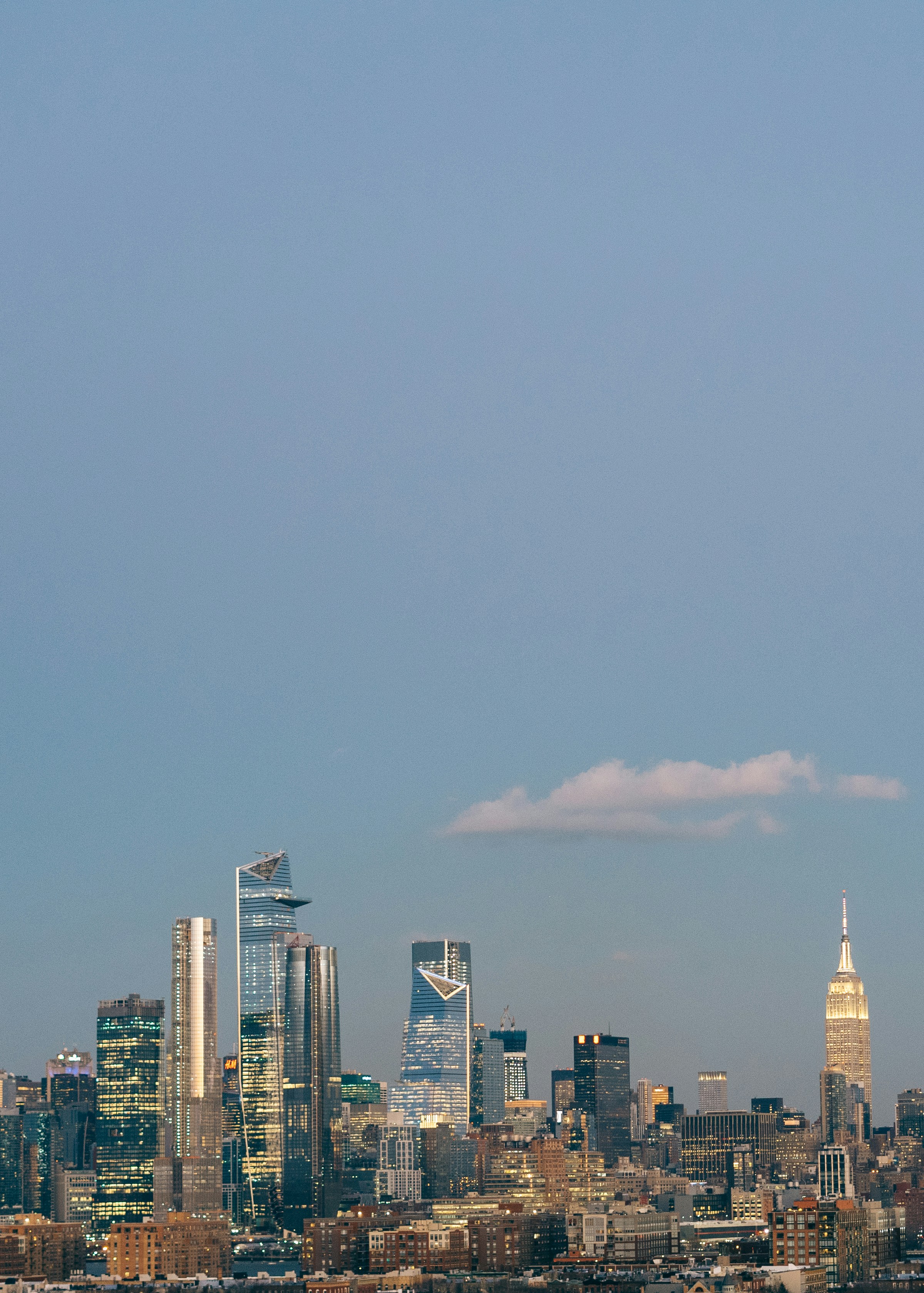 City skyline featuring a blend of modern skyscrapers and iconic architecture under a pastel twilight sky.
