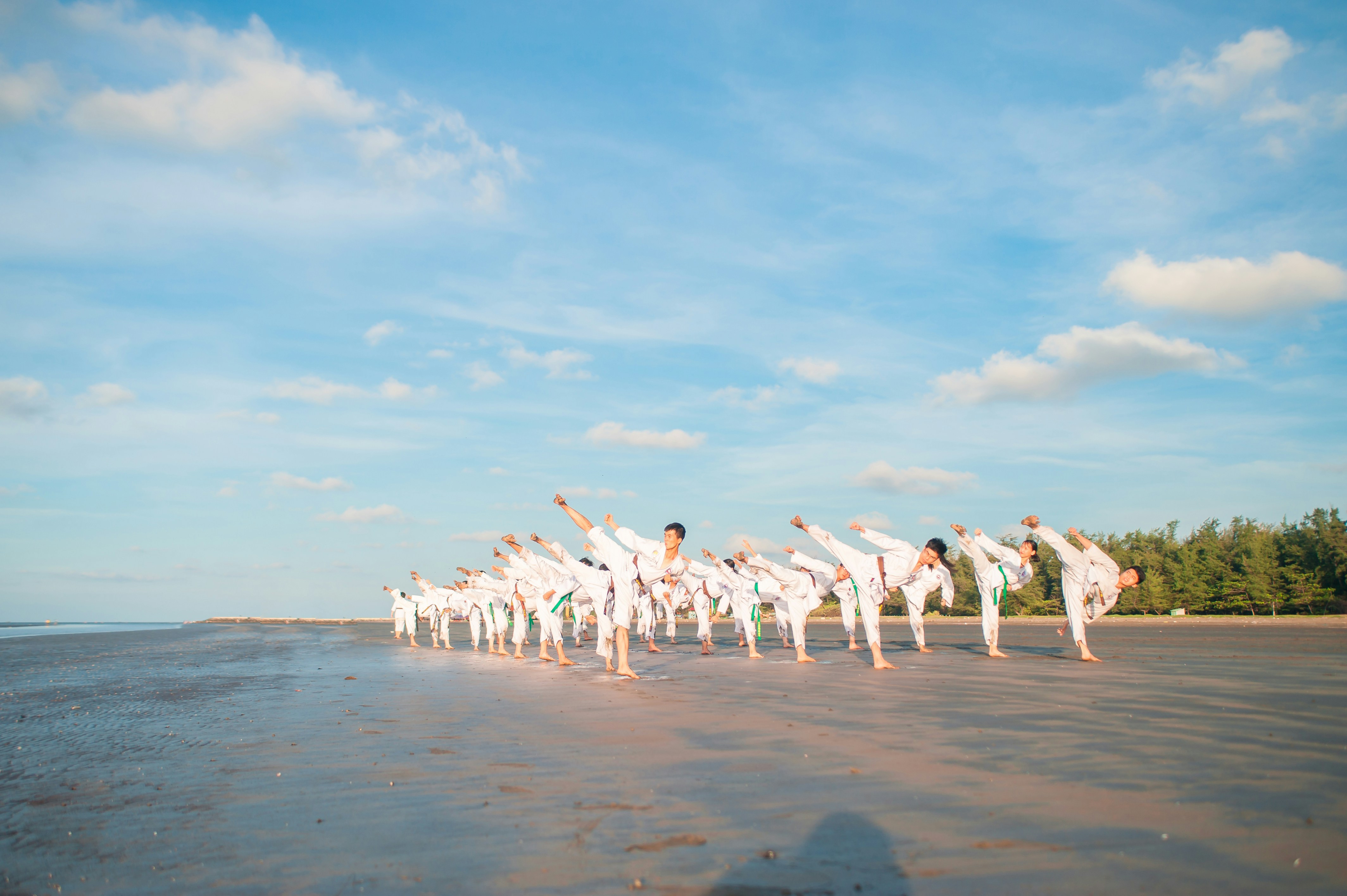 Group of people doing karate kick on body of water photo – Free Beach ...