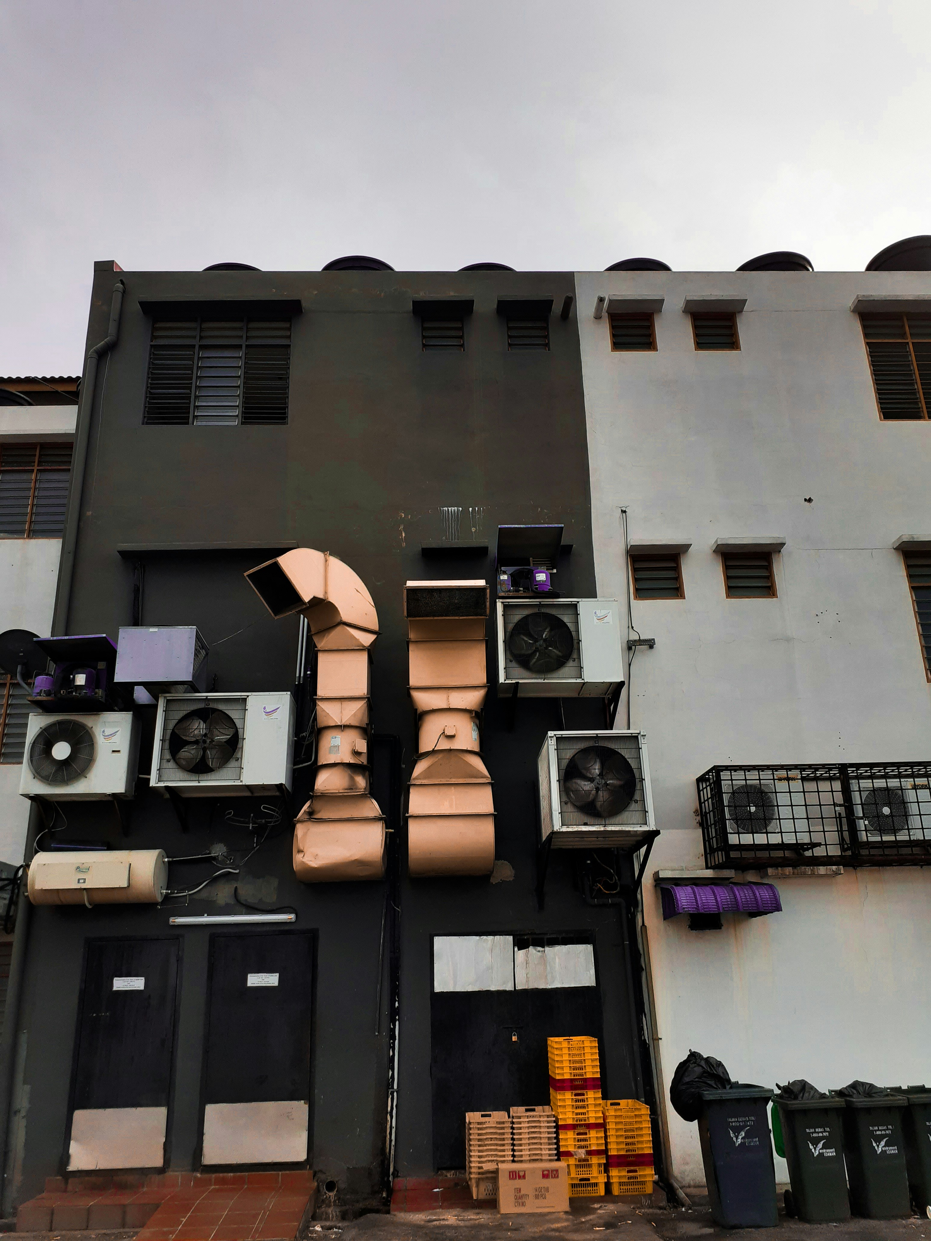 A wall adorned with various air conditioning units and ventilation ducts, showcasing the interplay of industrial design and urban architecture.